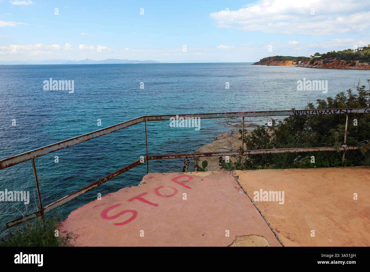 A weathered concrete platform with a rusted metal railing stands over ...