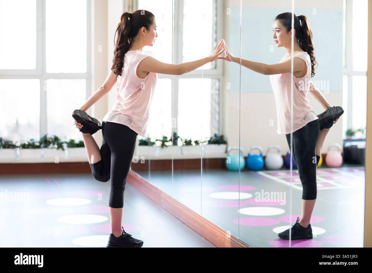 Chinese woman doing stretching exercise standing with one leg in front ...