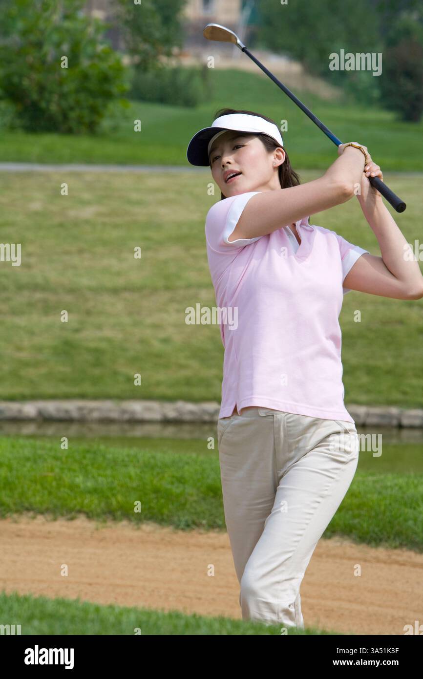 Portrait of a focused Chinese female golfer on the golf course ...