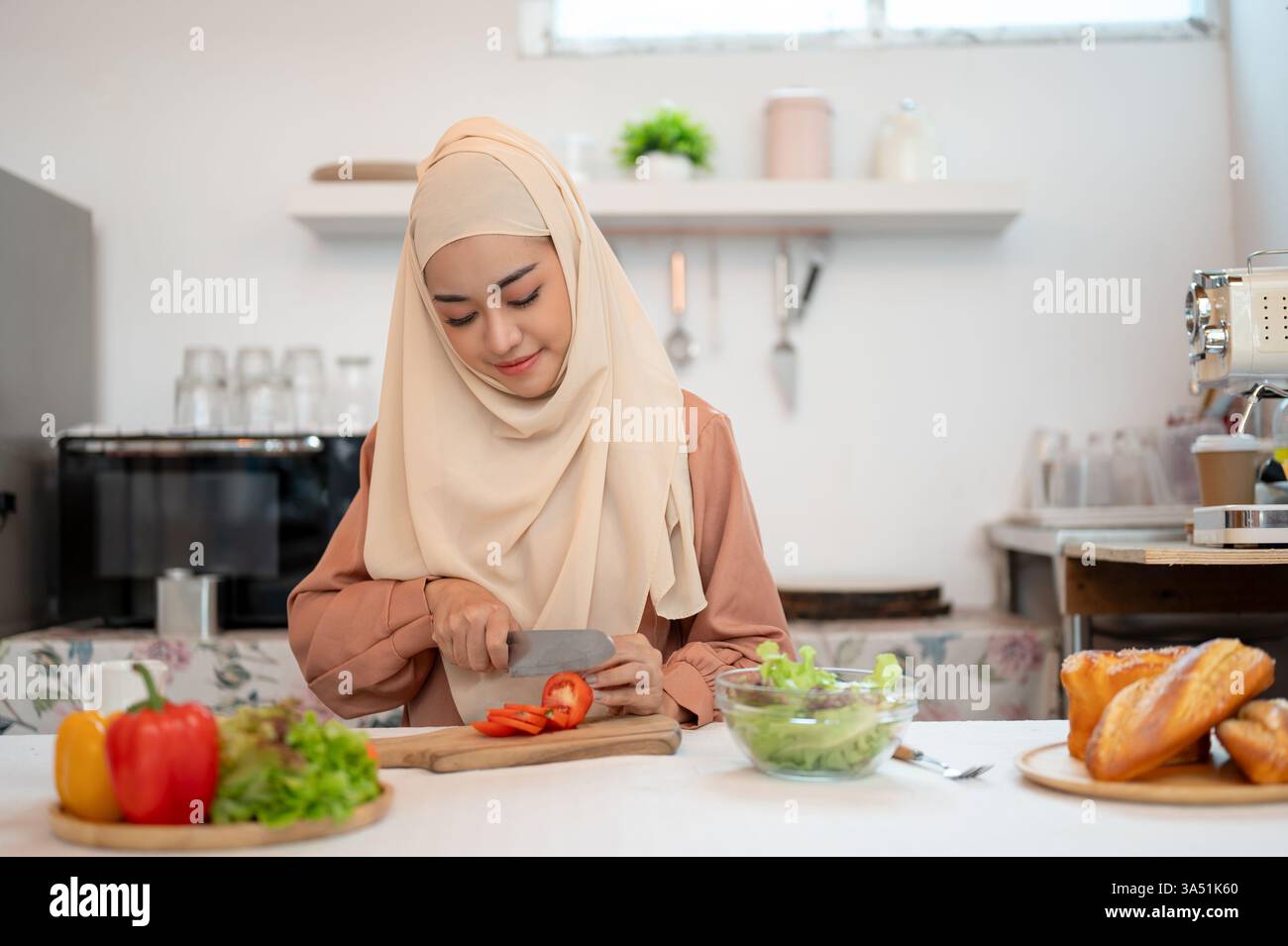 Asian Muslim woman wearing a hijab prepares healthy meals in a home ...
