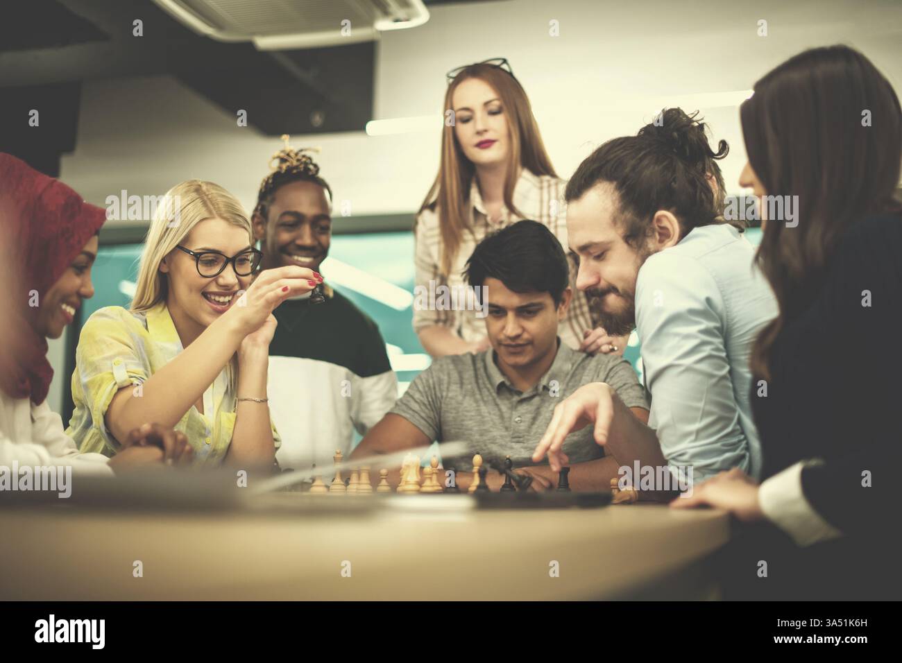 Focused diverse group of business people having fun playing chess while ...