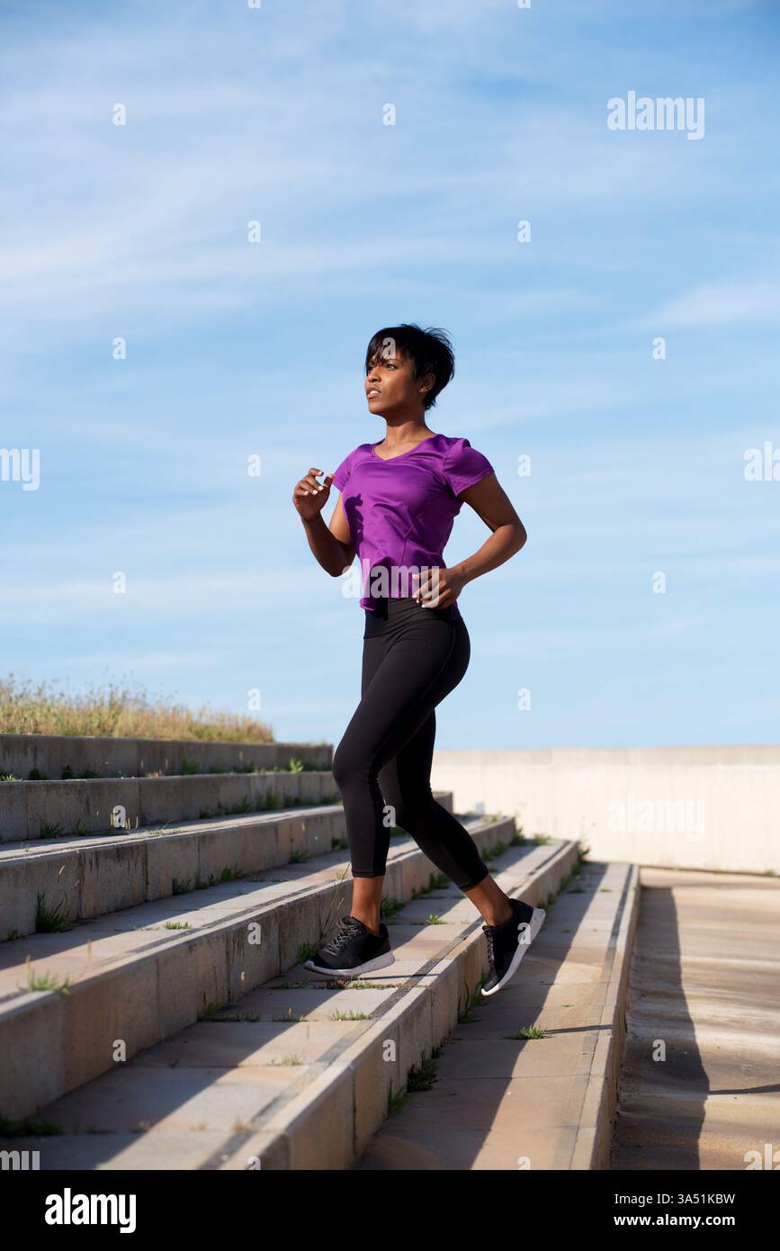 Portrait of fit young african woman running up stairs Stock Photo - Alamy