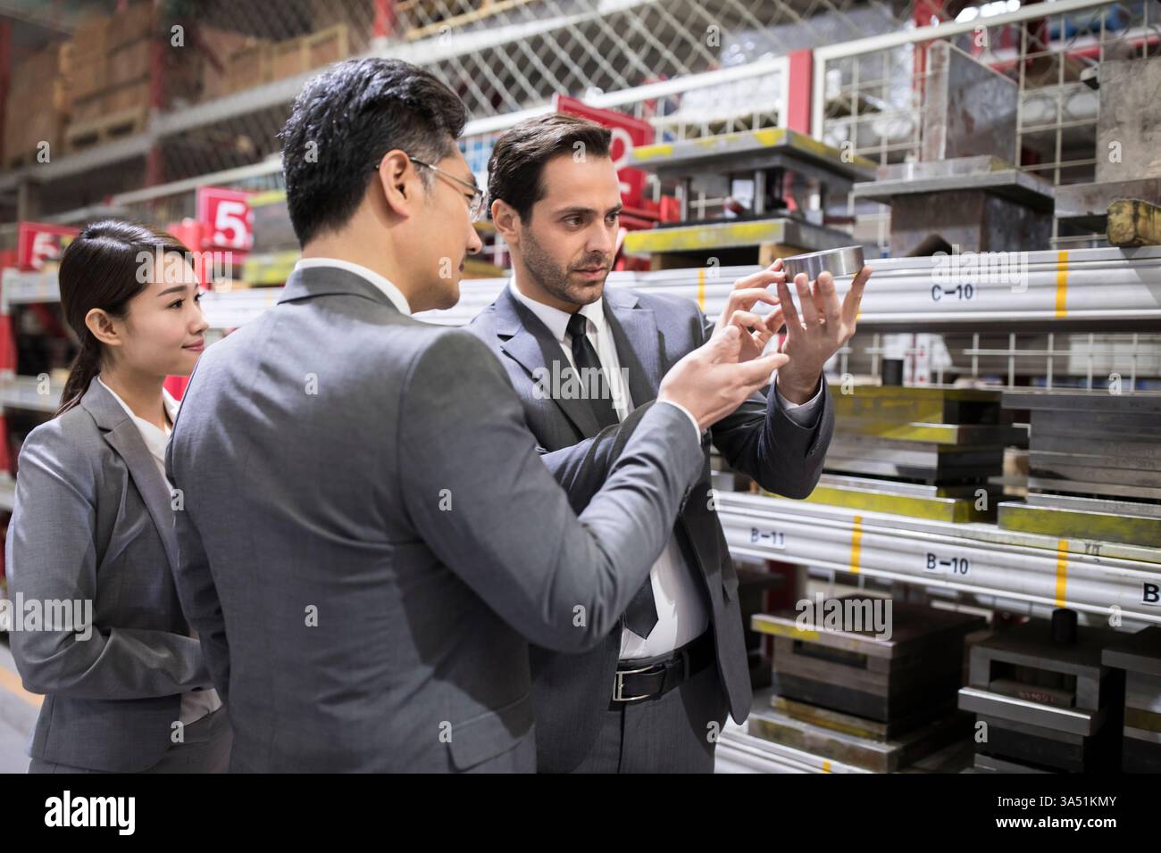 Hispanic and Chinese businessmen checking product with female assistant ...