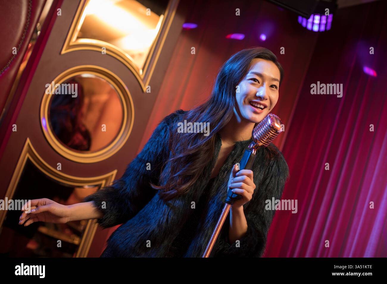 Chinese woman holding microphone singing karaoke in night club Stock ...