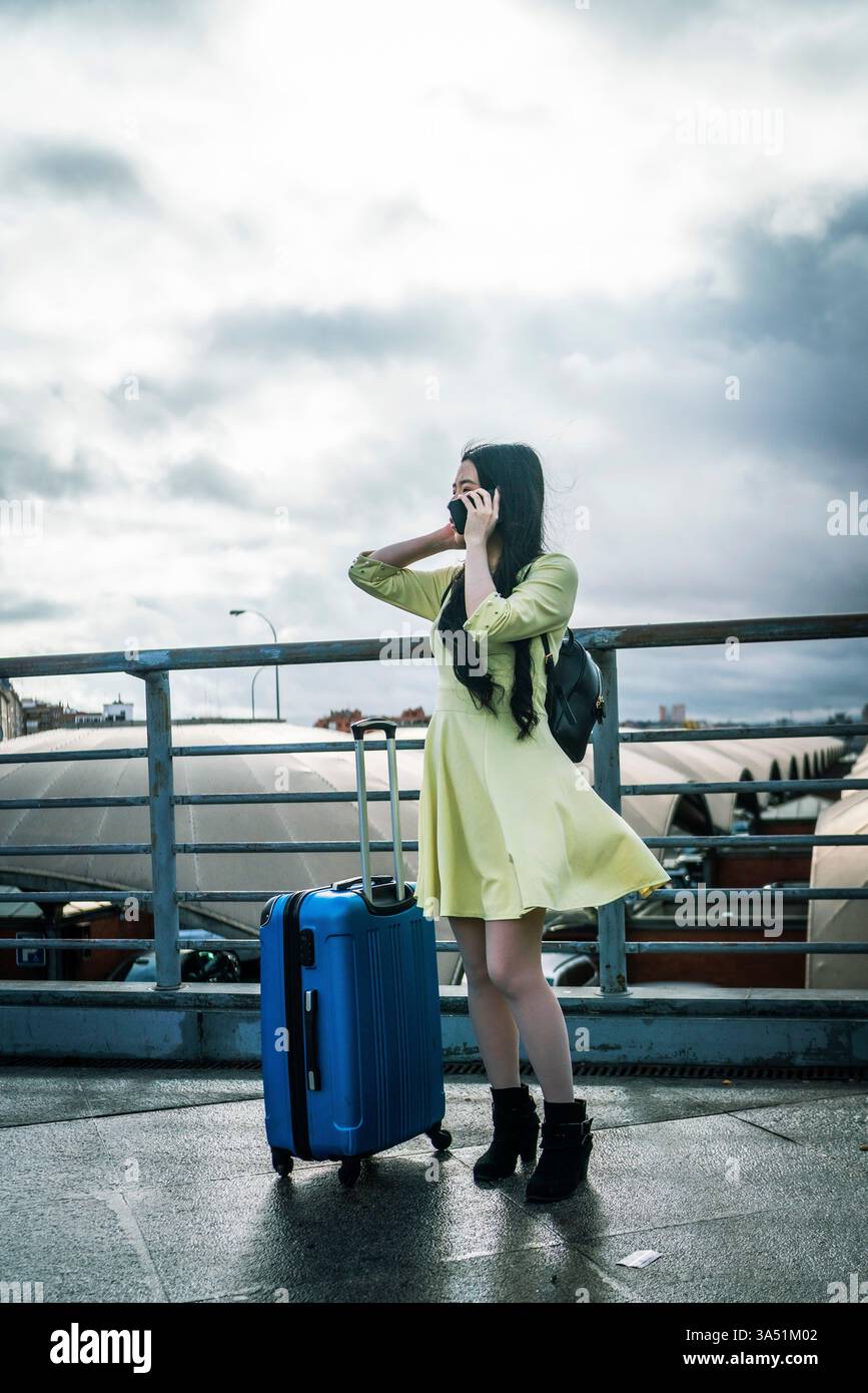A woman and her blue suitcase on her way to travel. The surroundings ...