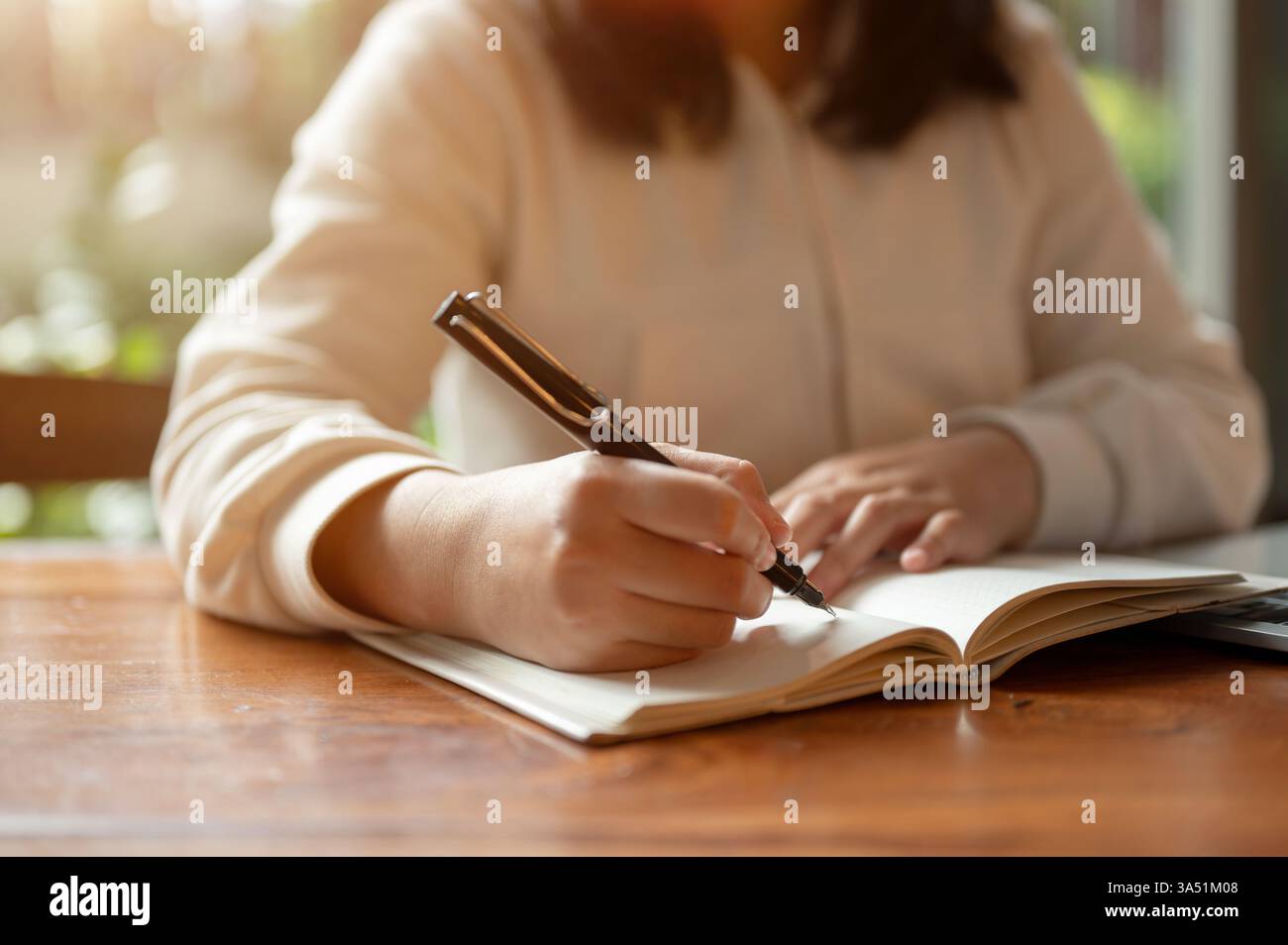 Cropped image of an Asian woman in casual clothes writing something in ...