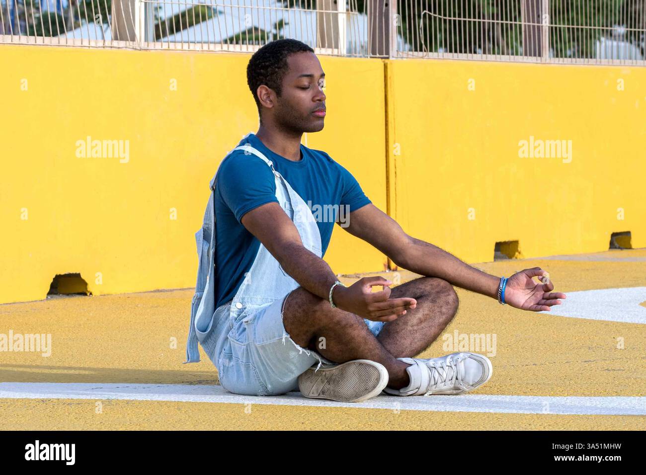 Serious Black man meditating with closed eyes and mudra hands while ...