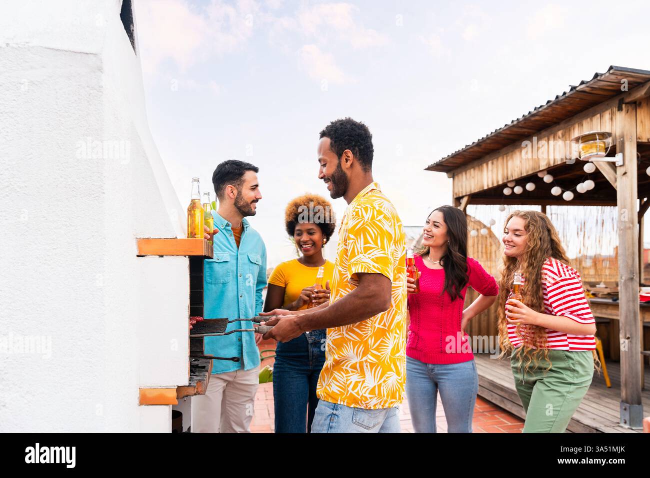 Cheerful diverse group of friends standing together and drinking beer ...