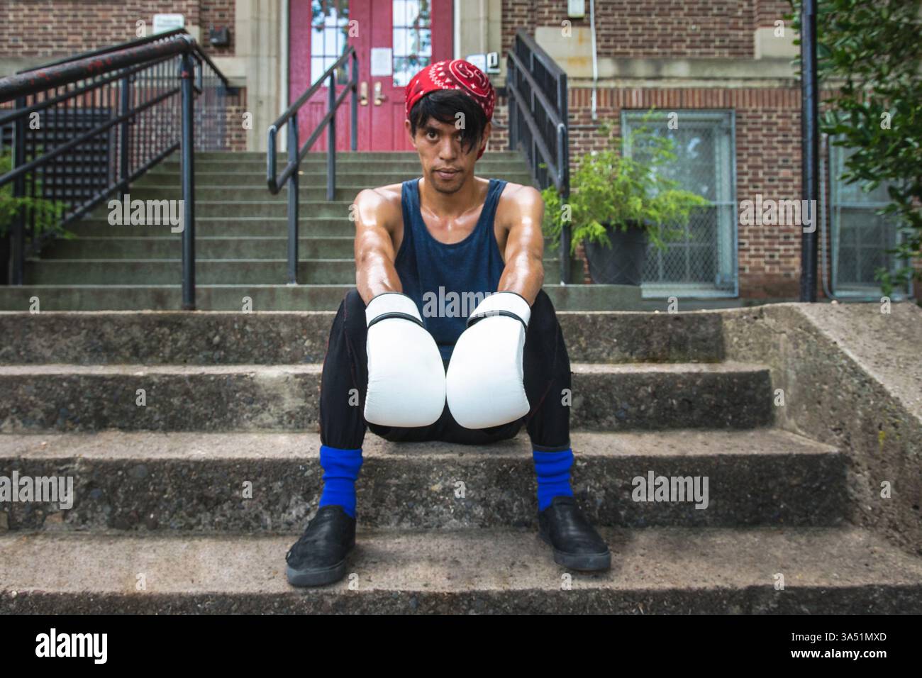 Asian guy sitting on stairs with boxing gloves on Stock Photo - Alamy