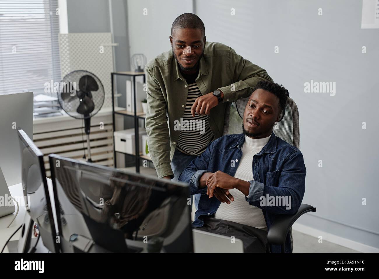 Two young colleagues of African ethnicity discussing working ...
