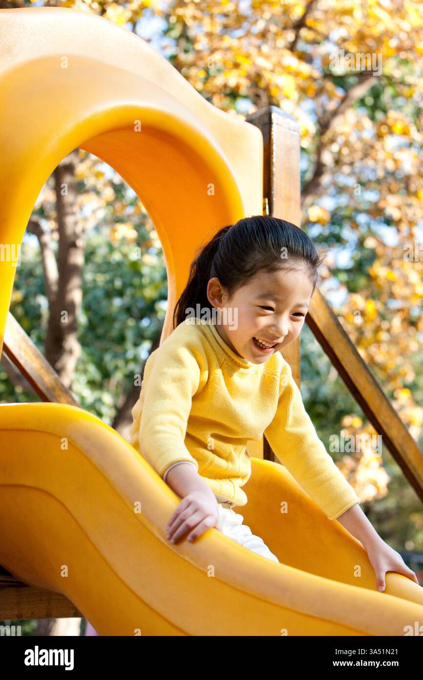 Chinese girl playing on playground slide Stock Photo - Alamy