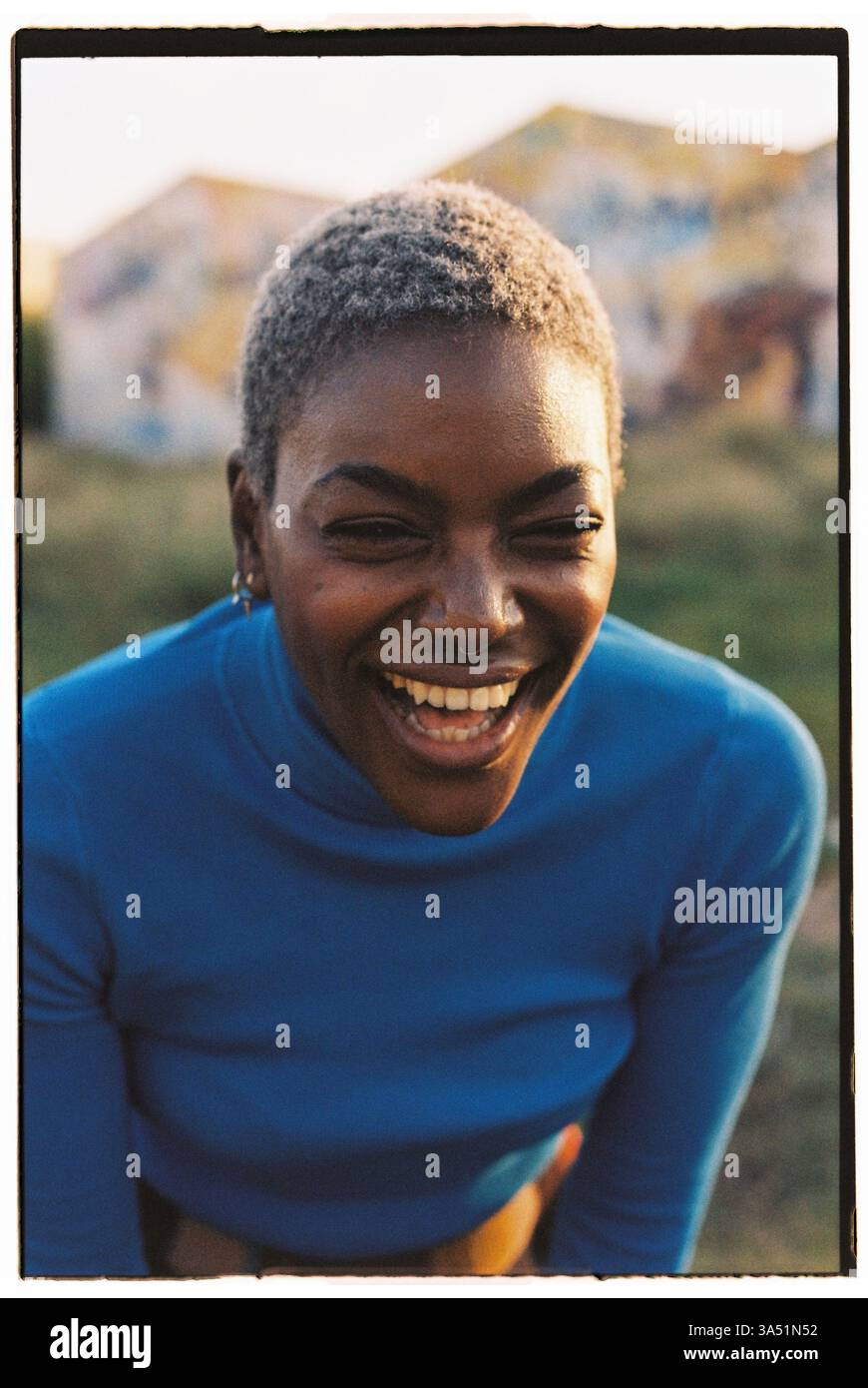 Black woman with short hair laughing standing on street on sunny day ...