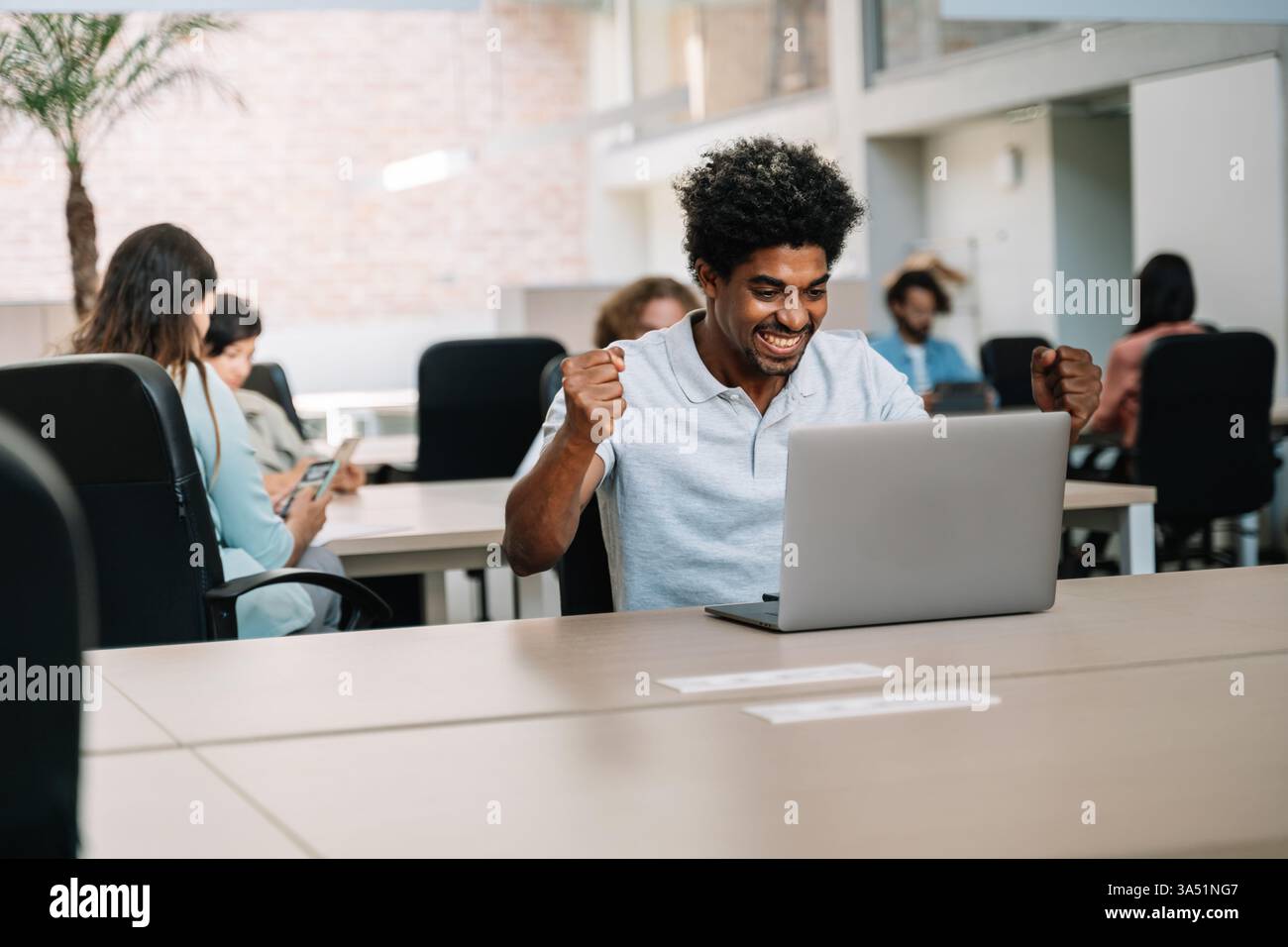 Happy Black man raising hand celebrating success sitting near ...