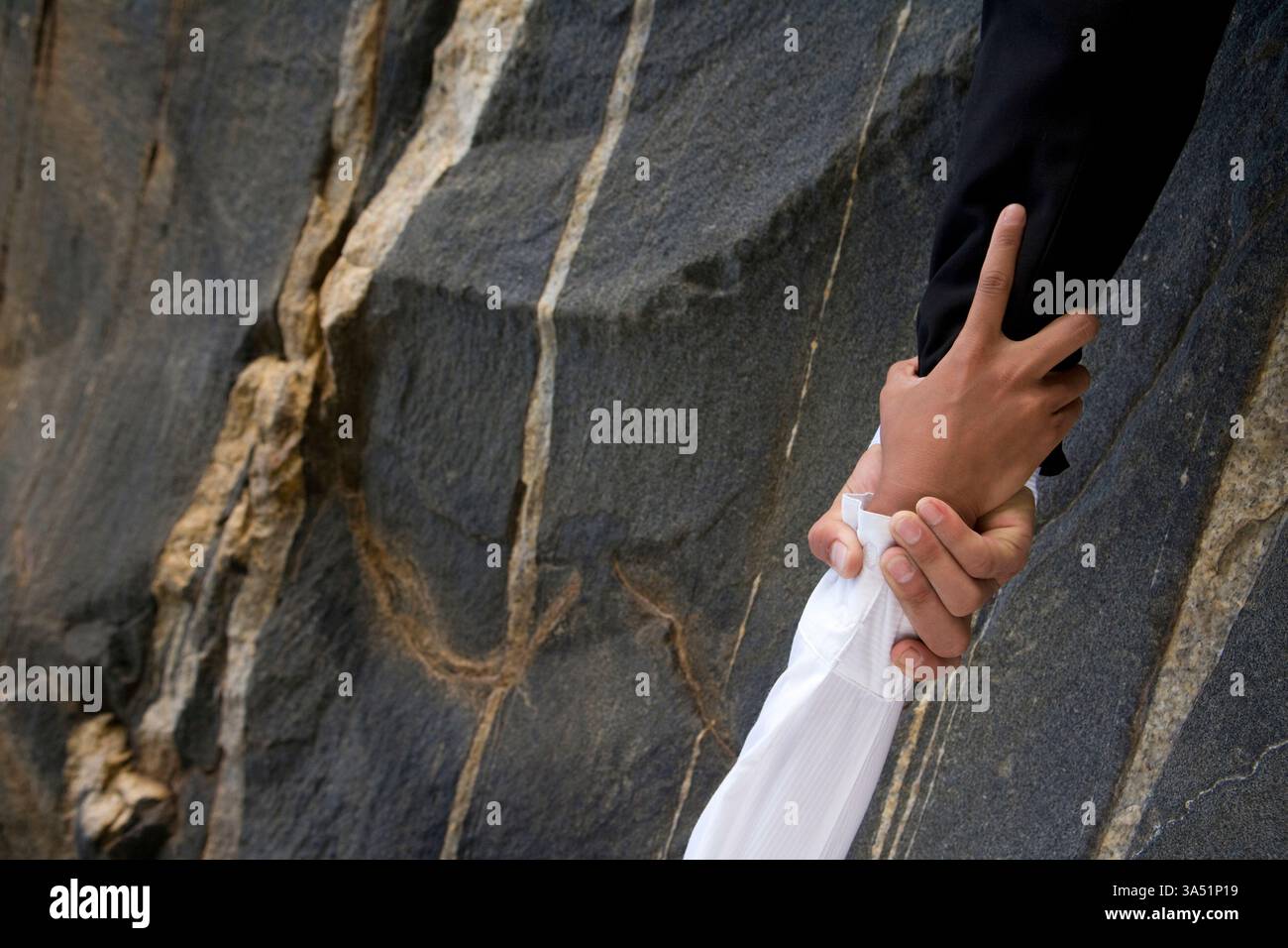 Two people cooperate on a rock climbing challenge outdoors ...
