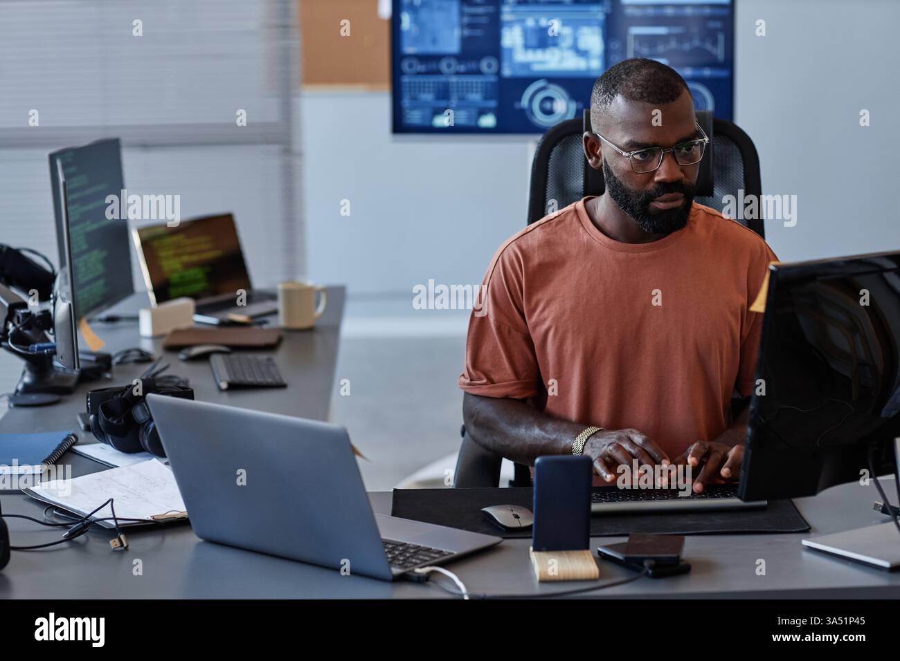 Portrait of young black man using computer in high technology office, data systems and ...