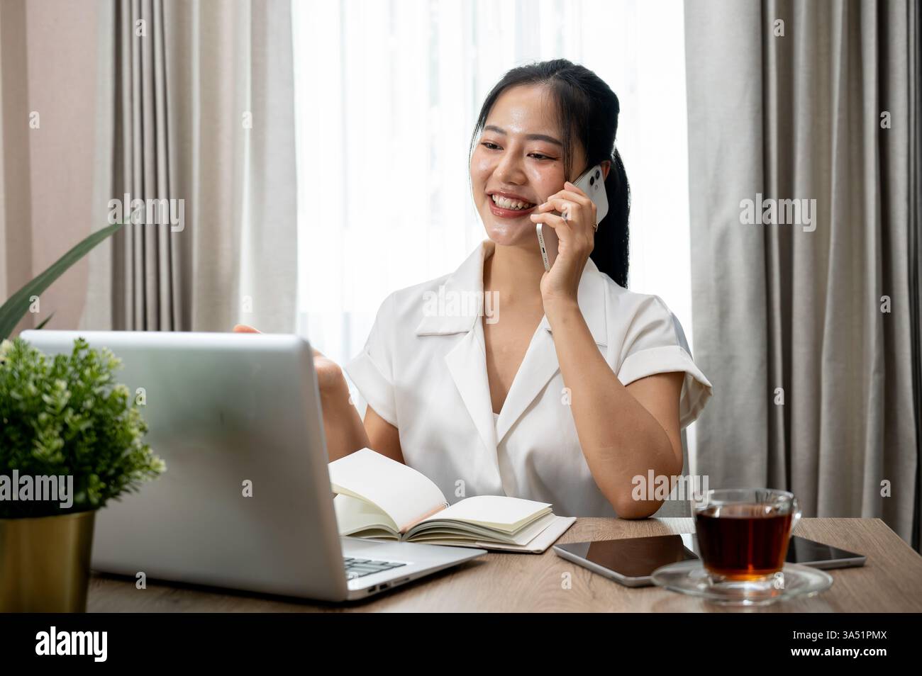 A confident, attractive Asian businesswoman is talking on the phone at ...