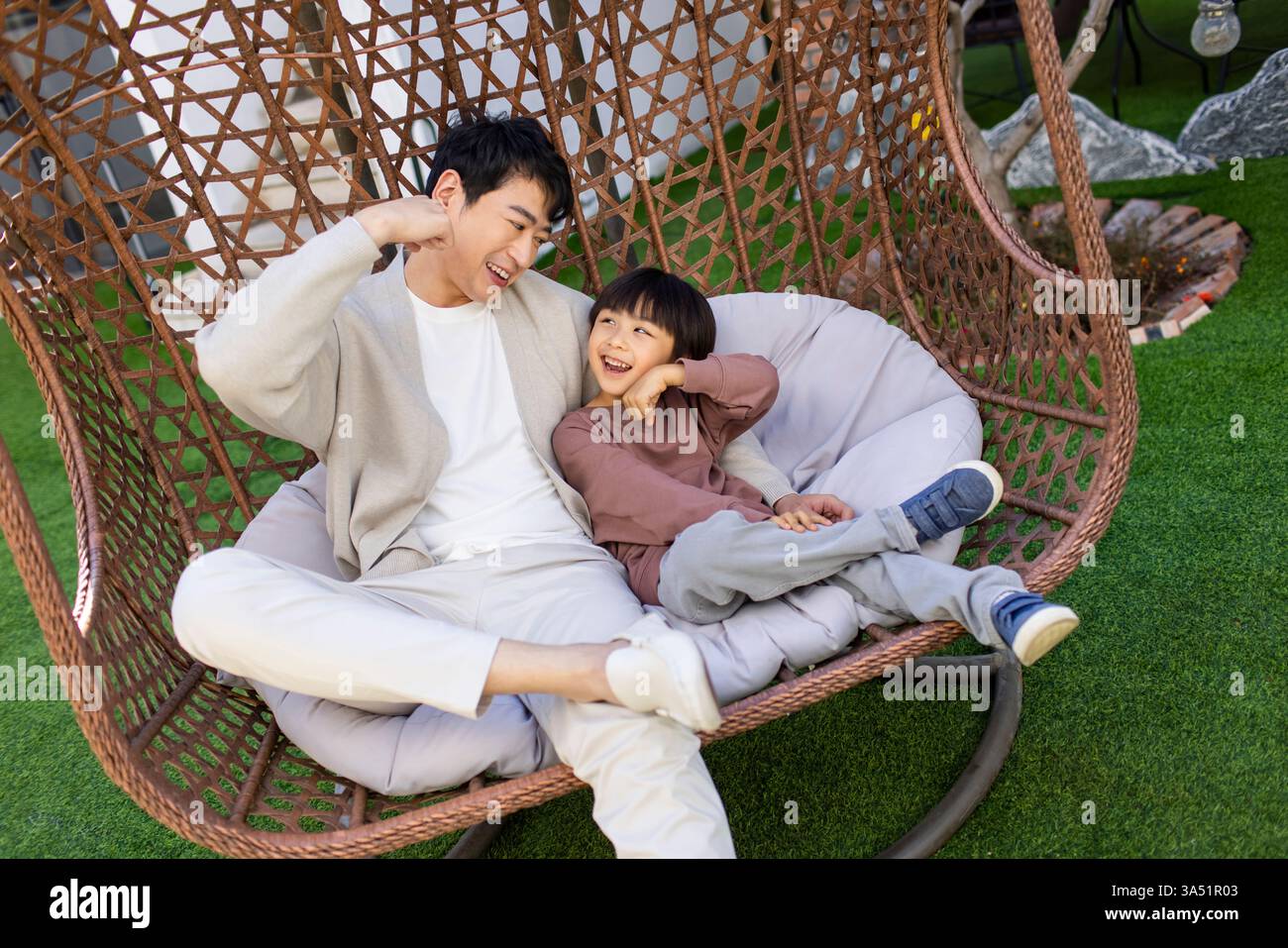 Happy little Chinese boy with his father on hanging-chair Stock Photo ...
