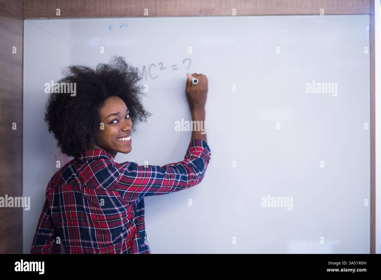 Cheerful Black female college student with afro standing and writing ...