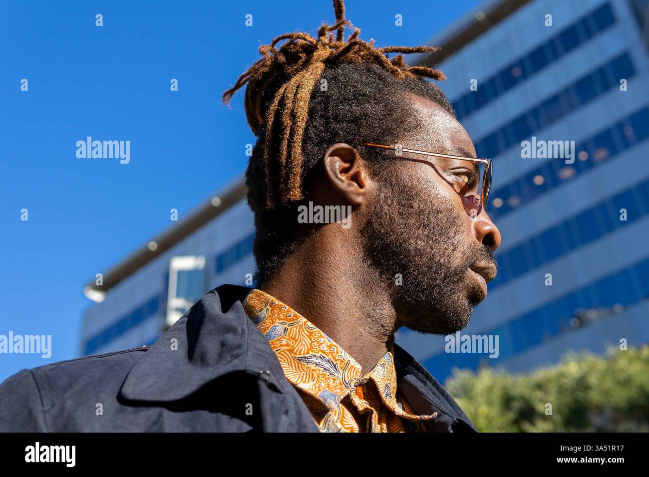 Black man looking over shoulder standing on street near building during ...