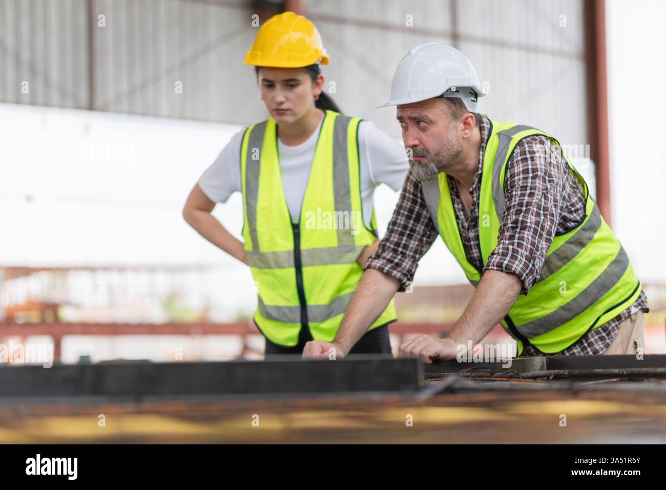 Hispanic female engineer with hardhat and safety vest discussing plan ...