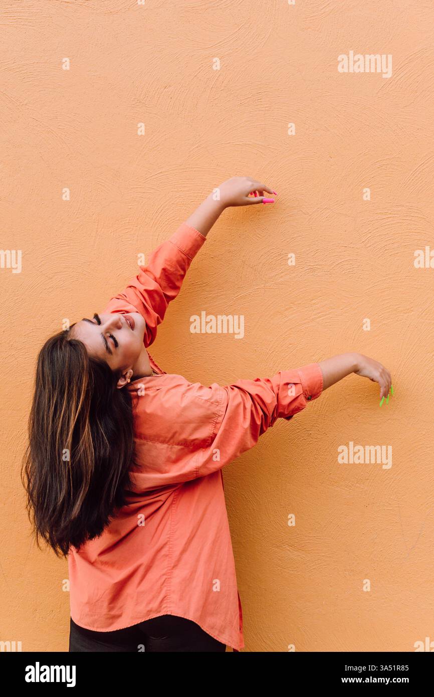 Hispanic female bending neck with closed eyes raising hands against ...