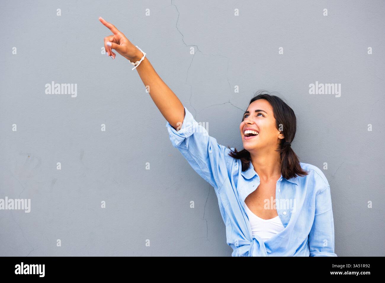 Portrait smiling young woman pointing finger by gray background Stock ...