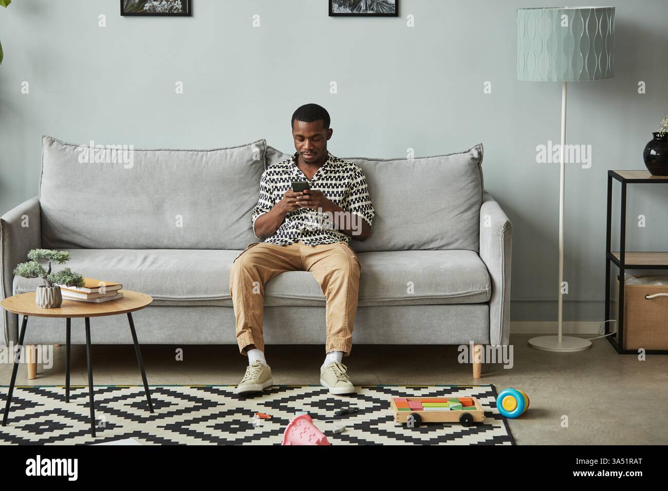 Full length portrait of young black man using smrartphone while ...