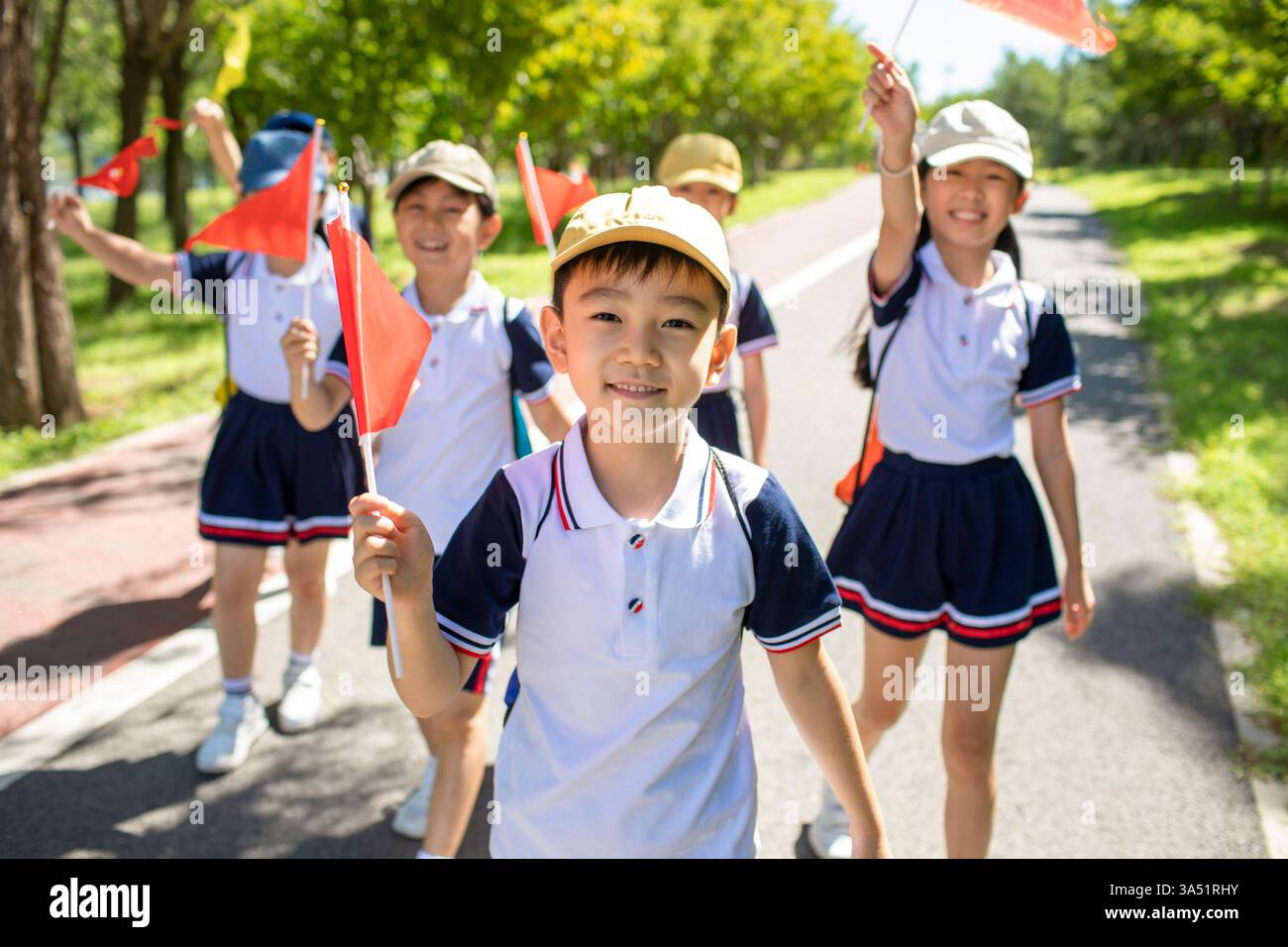 Smiling Chinese boy with classmates in school uniforms wearing hats ...