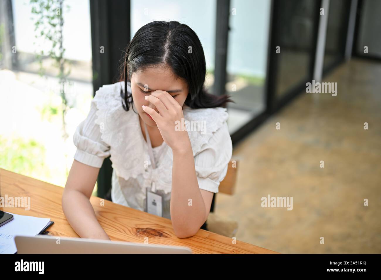 Stressed and tired young Asian female office worker suffering from ...