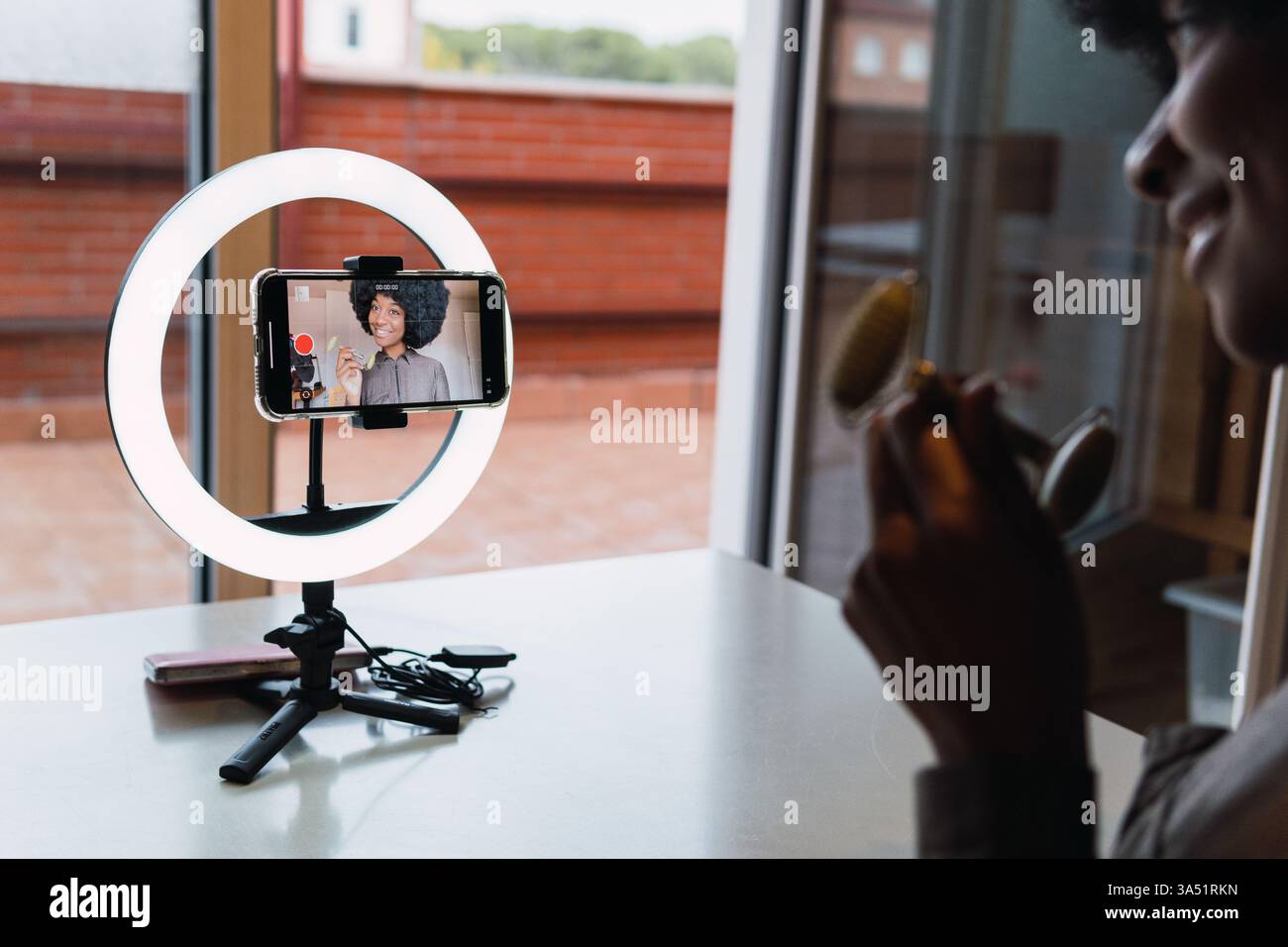 Black female vlogger holding ridge jade face roller while recording ...