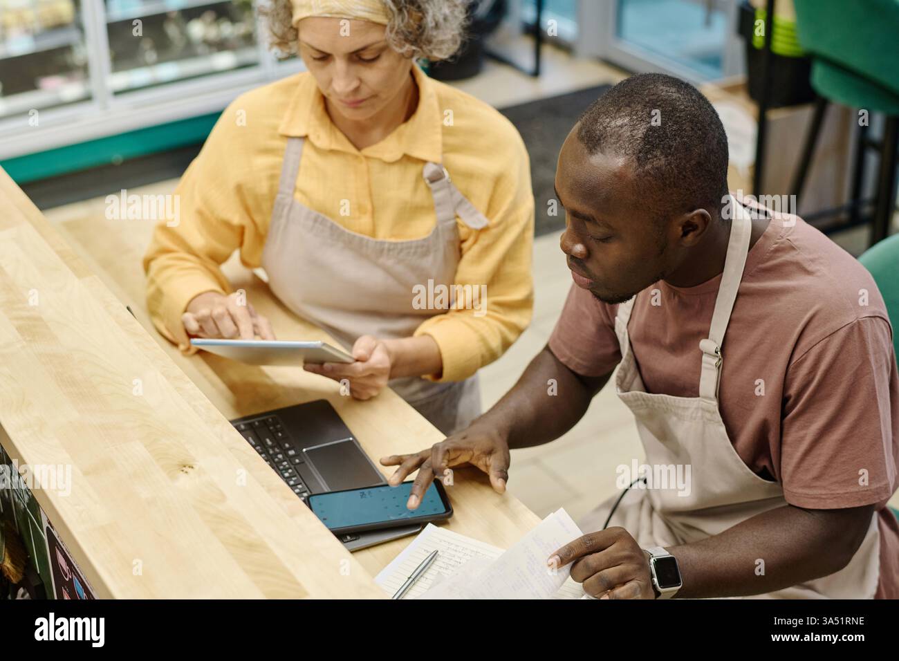 Black male store clerk wearing apron using mobile phone calculator ...