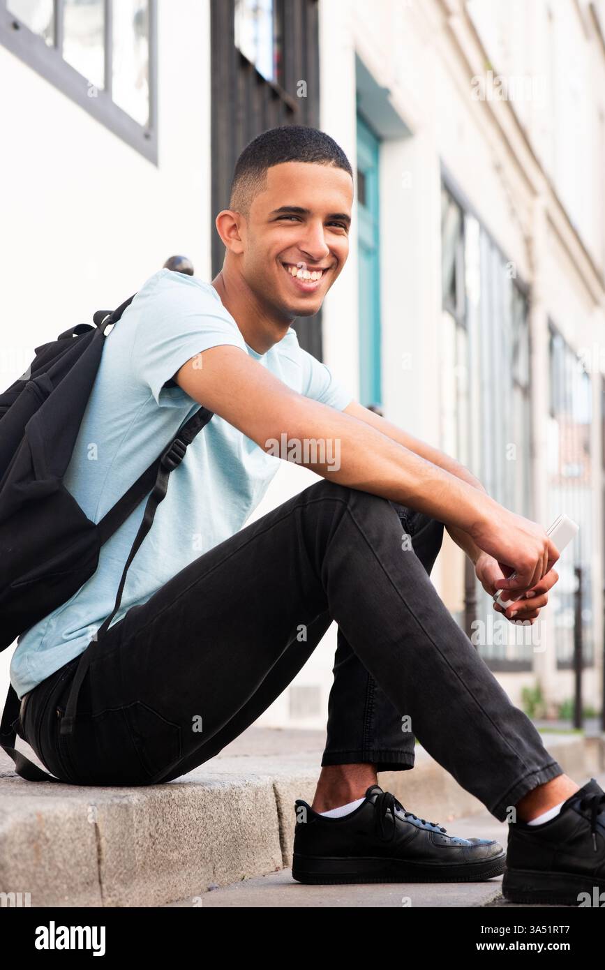 Arab male leaning arms on knees sitting on sidewalk near building ...