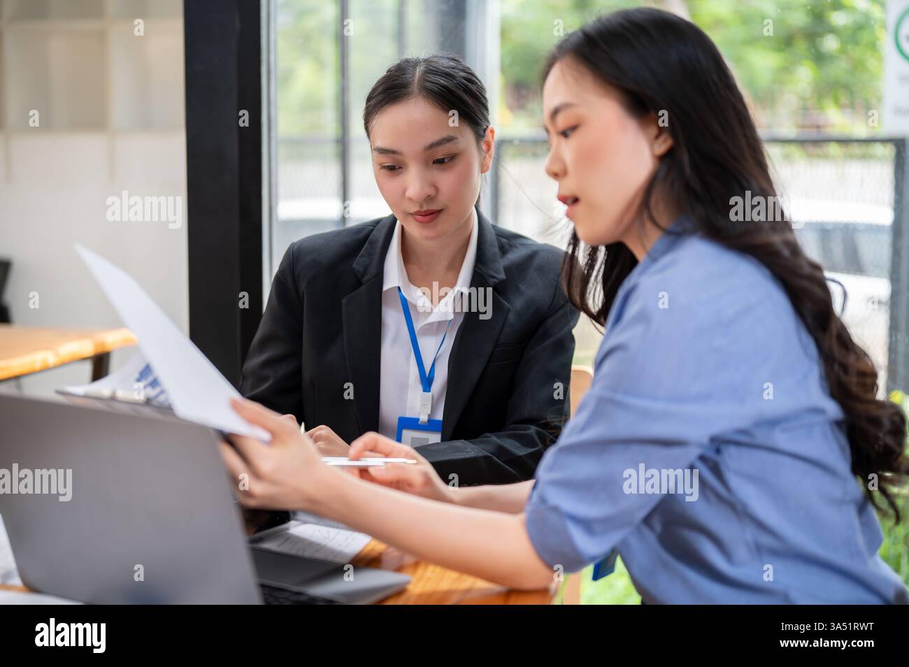 A professional and focused millennial Asian businesswoman in a formal black suit is having a ...