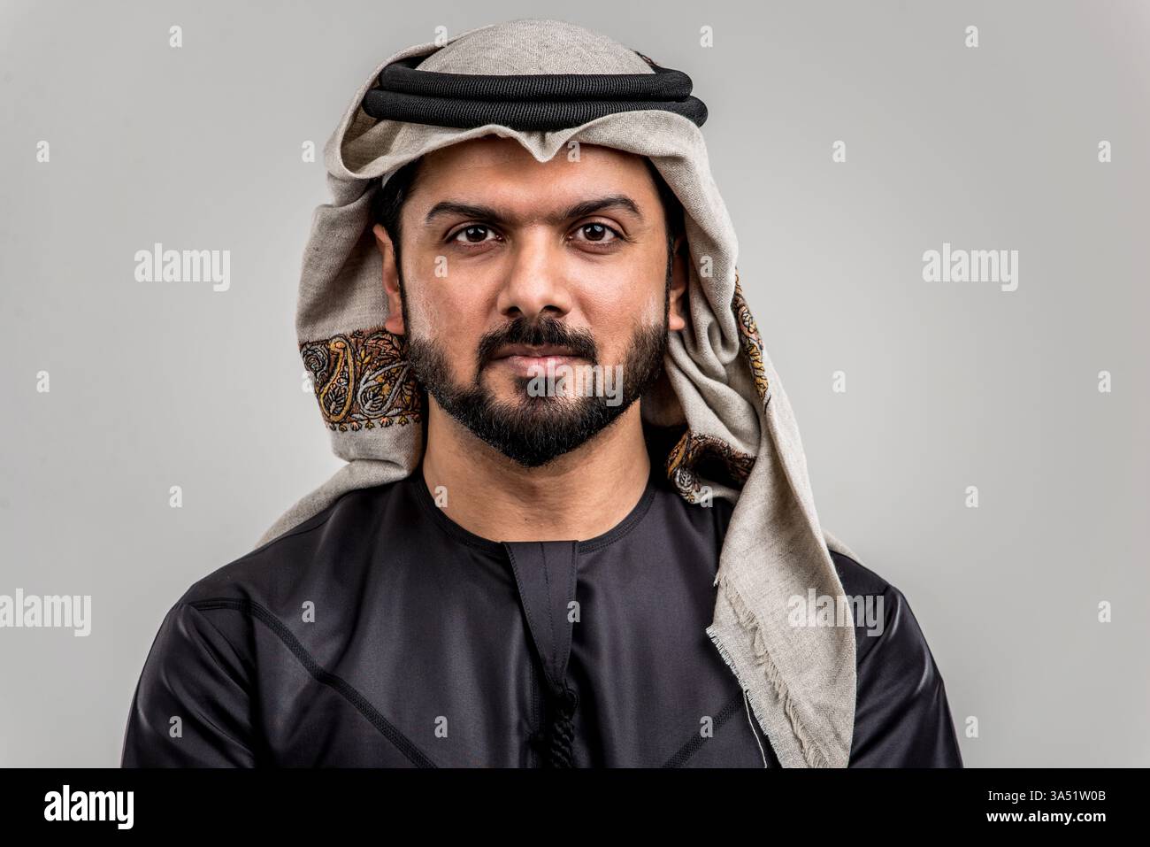 Serious Middle Eastern man standing against gray background Stock Photo ...