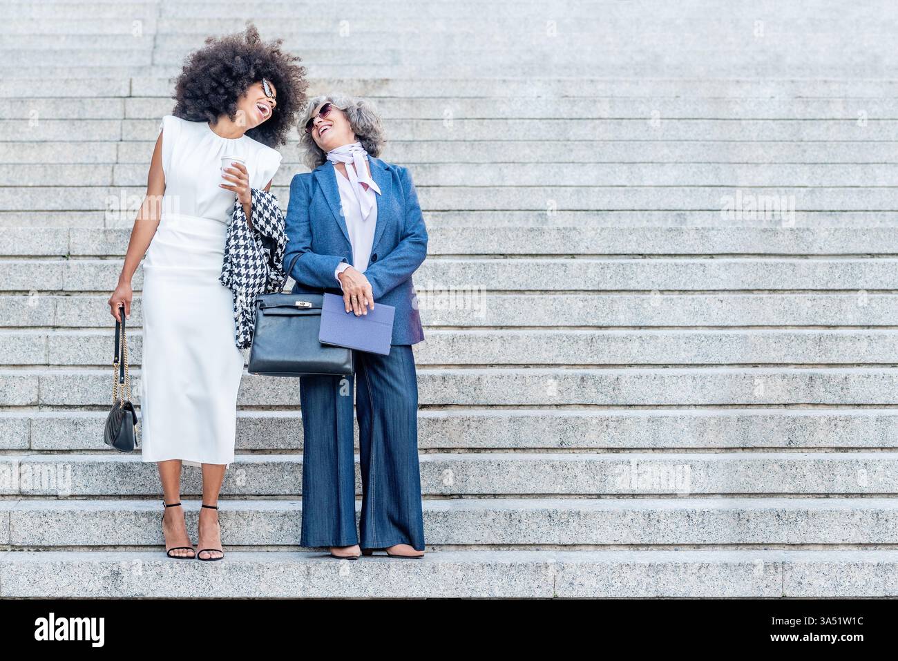 Hispanic and caucasian senior woman laughing while standing on stairs ...