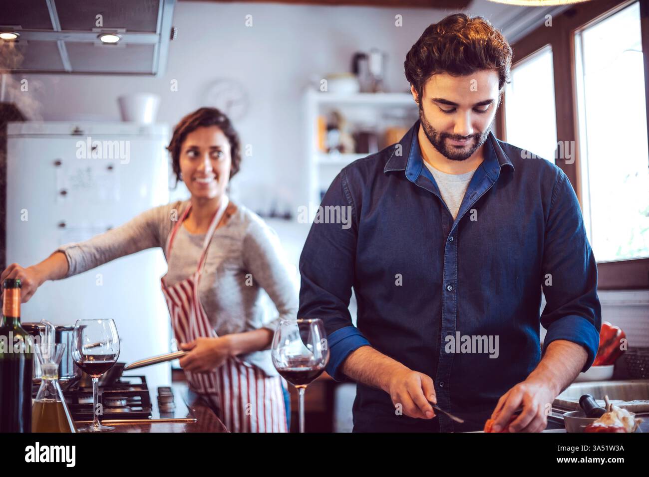 Hispanic couple cooking together in a home kitchen. Warm lifestyle ...