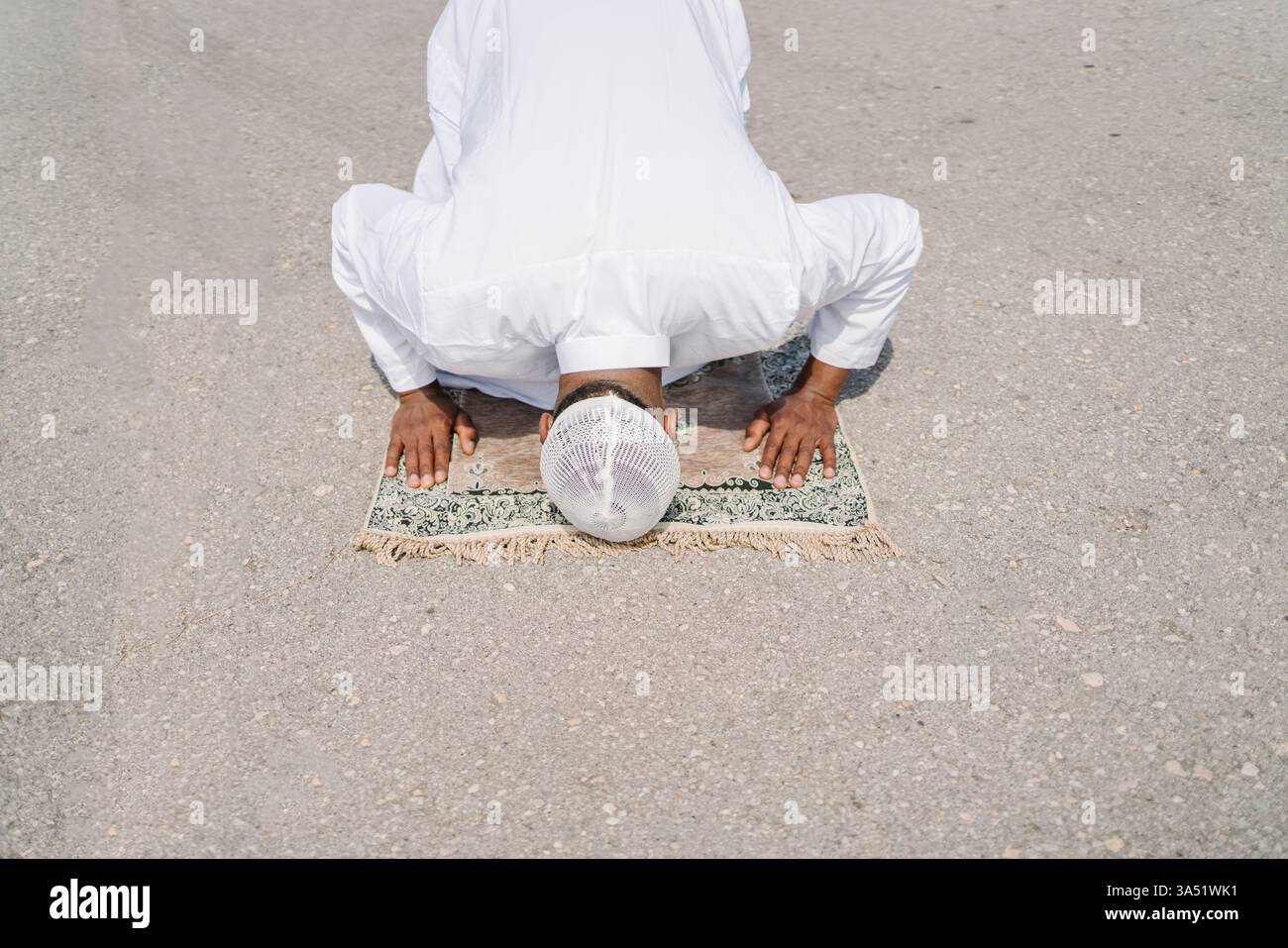Muslim man kneeling and bowing head on prayer mat on empty road Stock ...