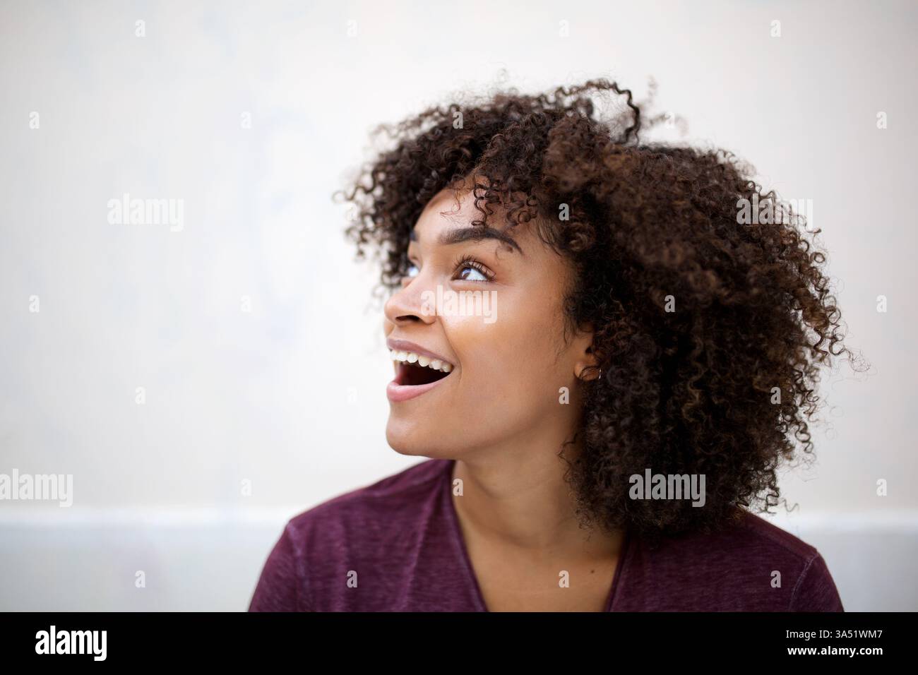 Smiling Black female with mouth open looking sideways standing against ...