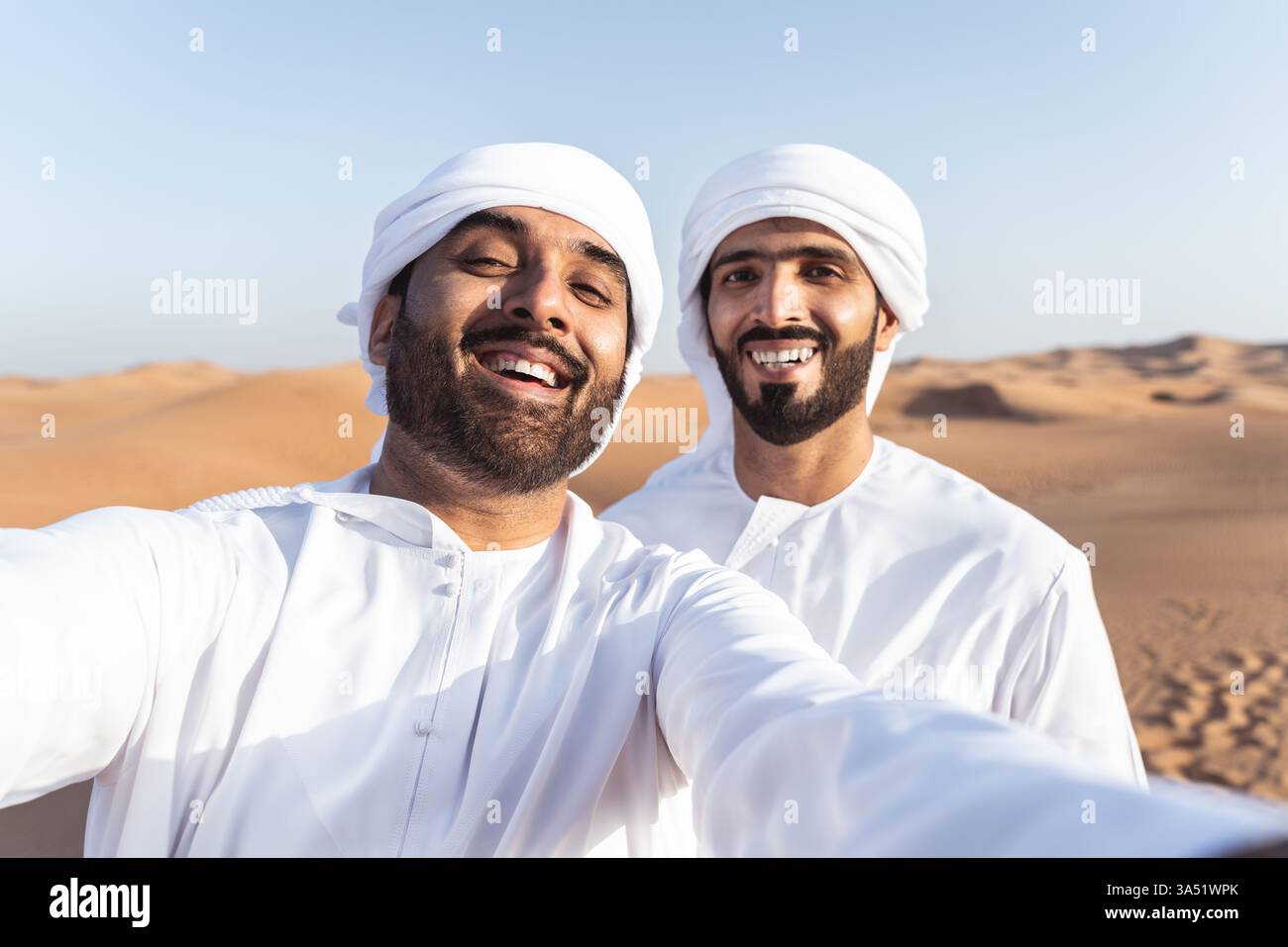 Two middle-eastern men wearing traditional emirati arab kandura bonding ...