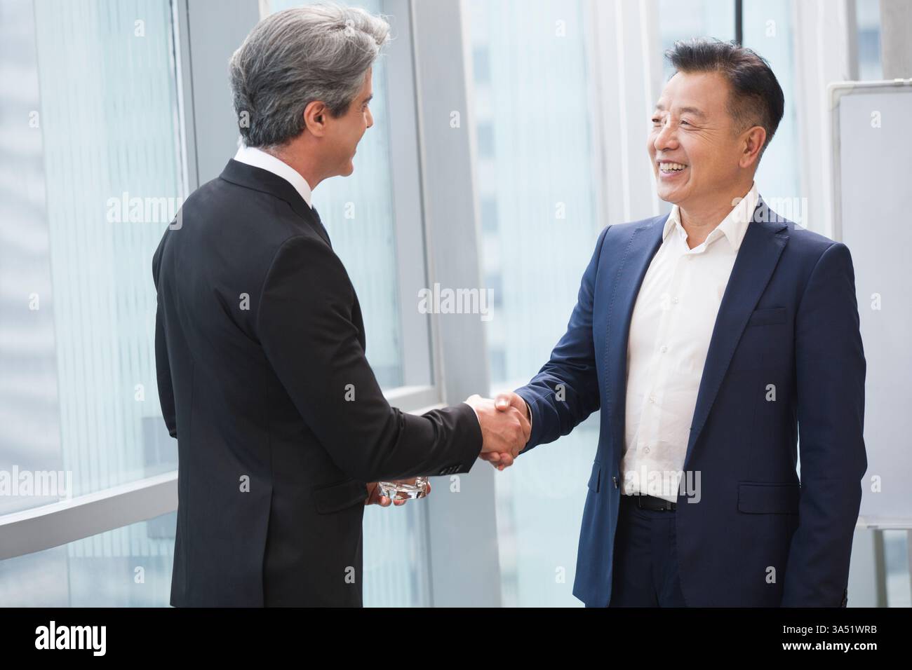Chinese businessmen shaking hands in meeting room Stock Photo - Alamy