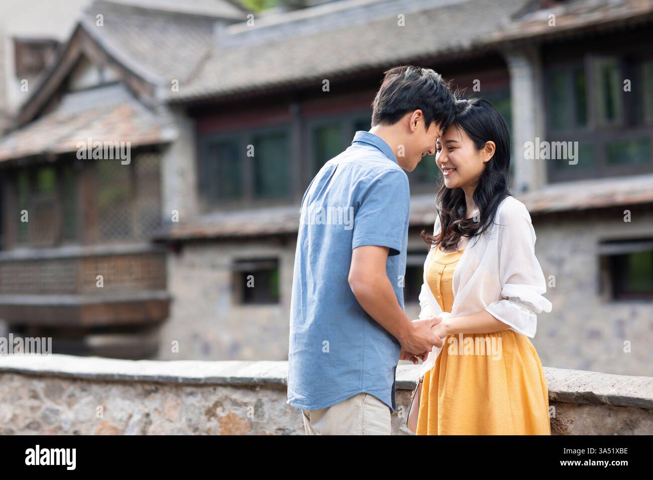 Chinese couple touching heads holding hands standing on bridge during ...