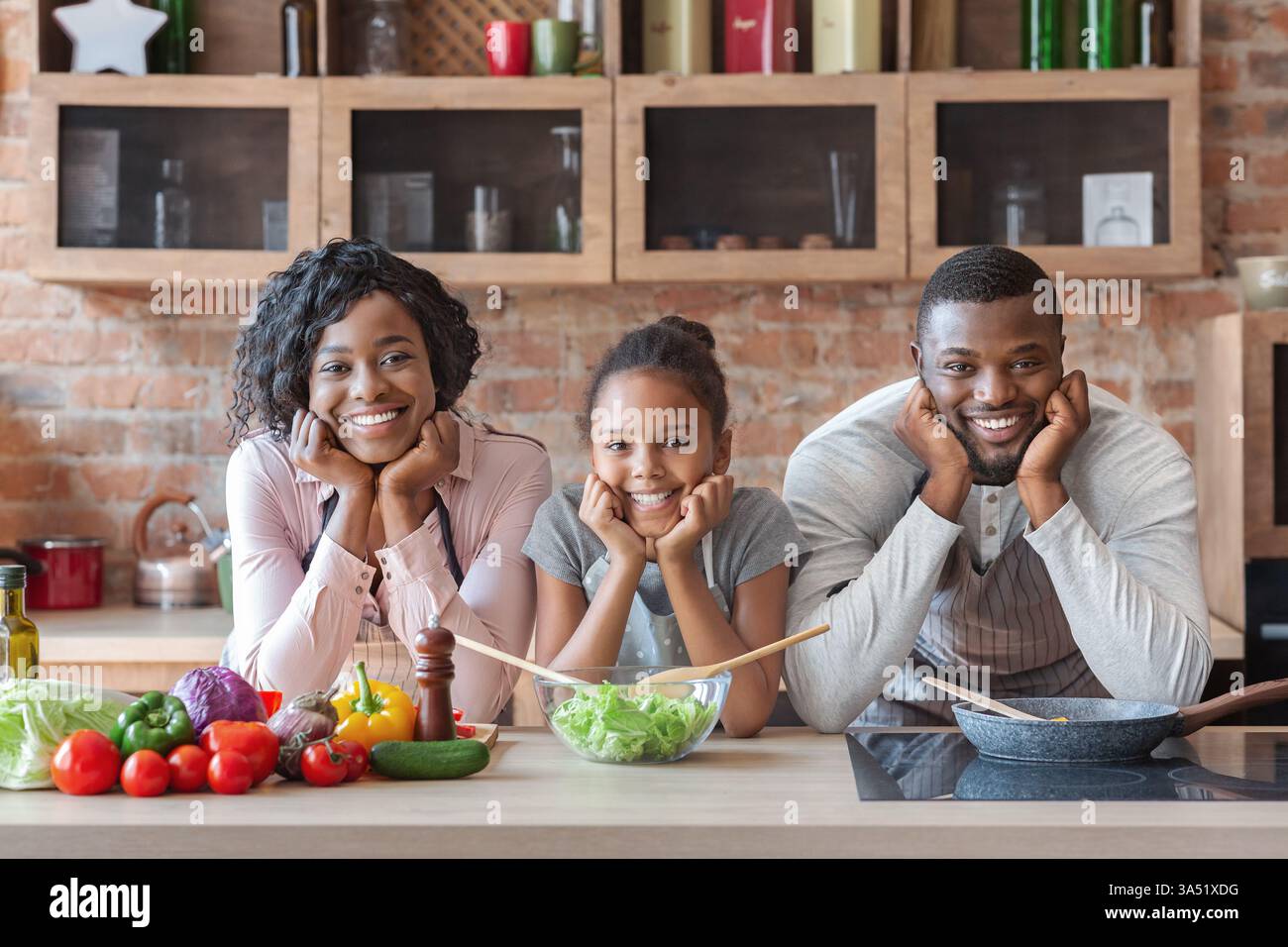 Beautiful black family making healthy dinner together, leaning their ...
