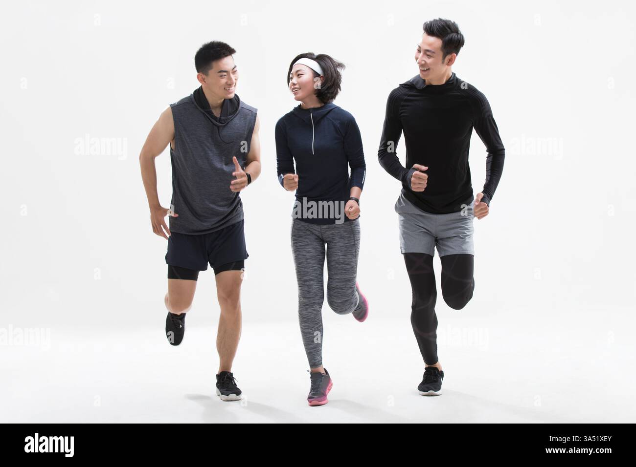 Chinese friends running together against white background in studio ...