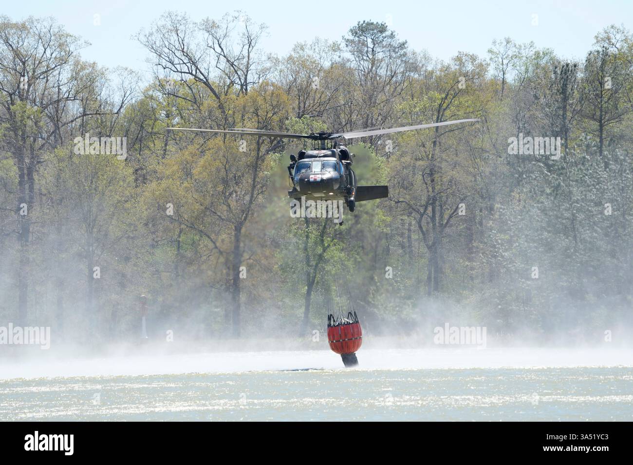 A helicopter drops a bucket to gather water to battle the Pauline Road ...