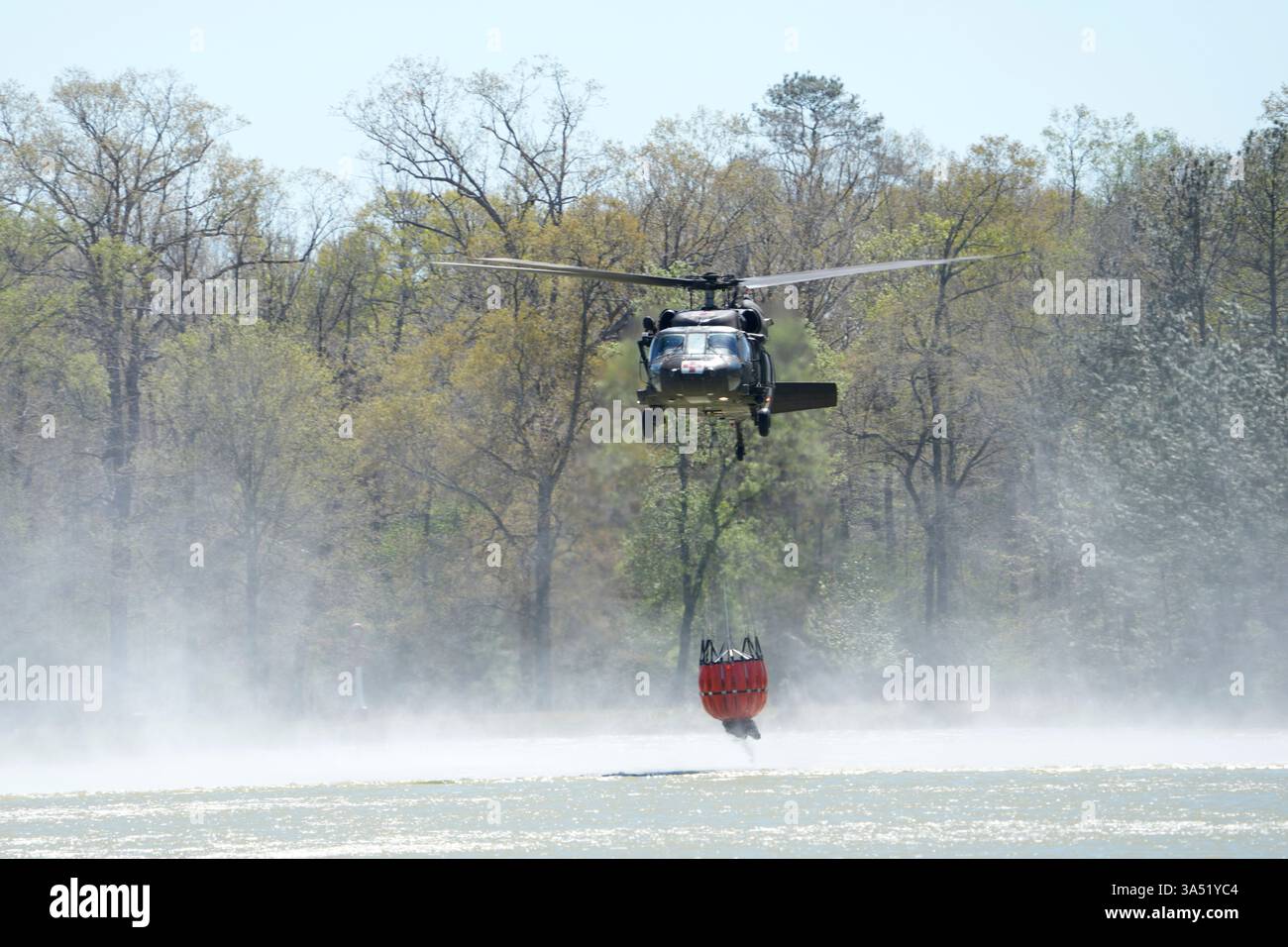 A helicopter drops a bucket to gather water to battle the Pauline Road ...