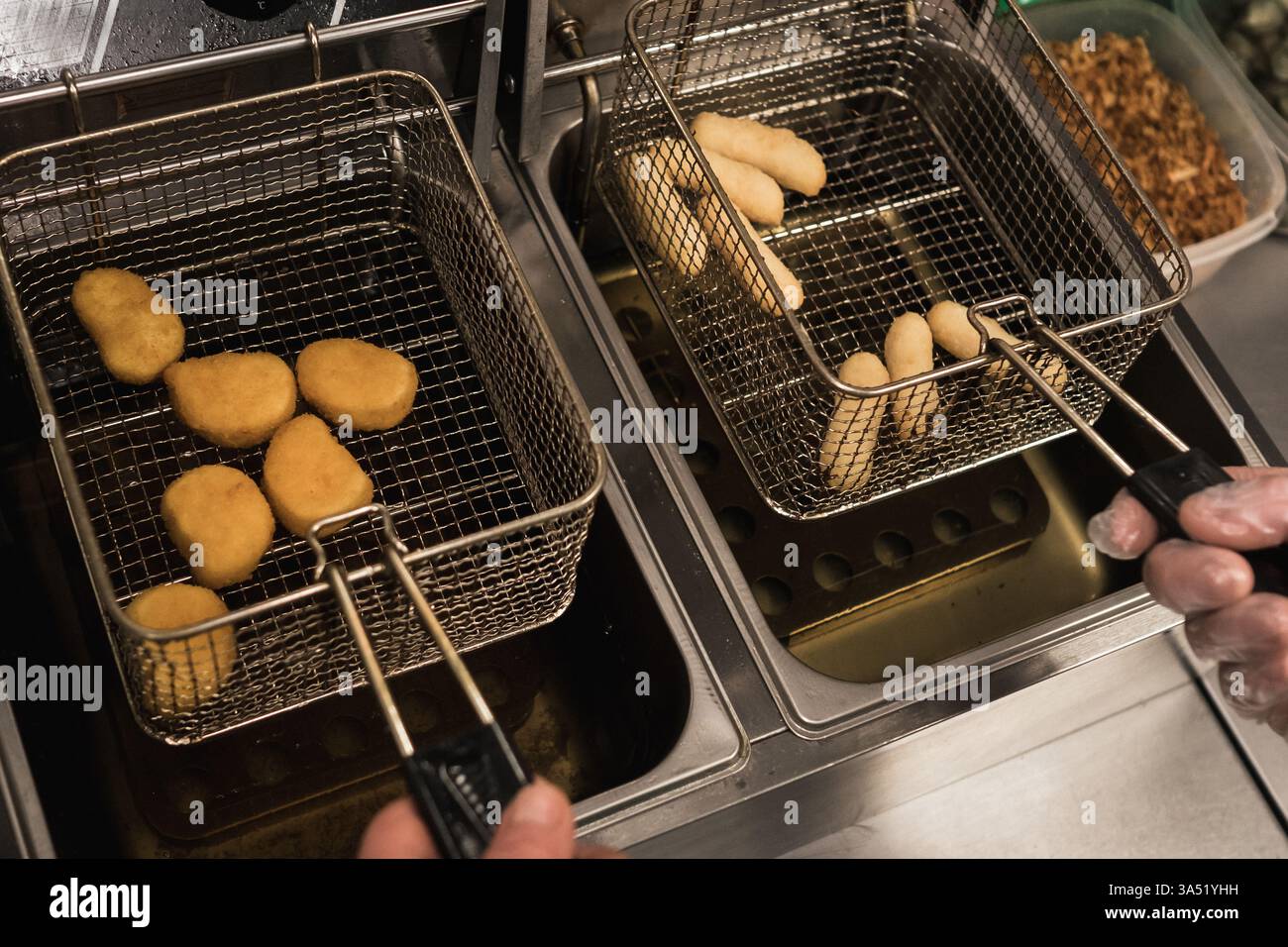 Fried snacks cooking in deep fryer with various shapes and sizes being ...