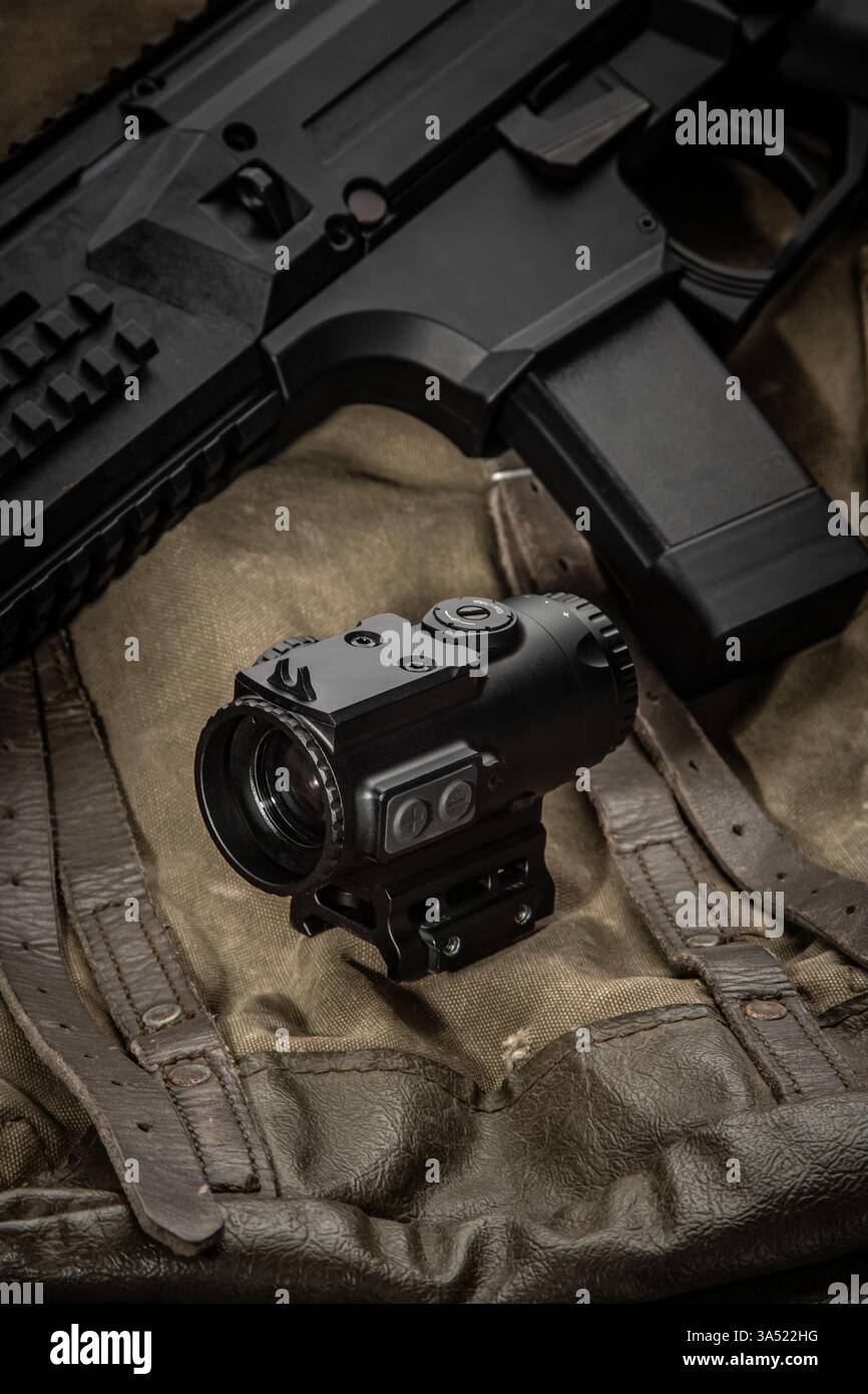 A tactical rifle with a mounted scope and a separate optical sight ...