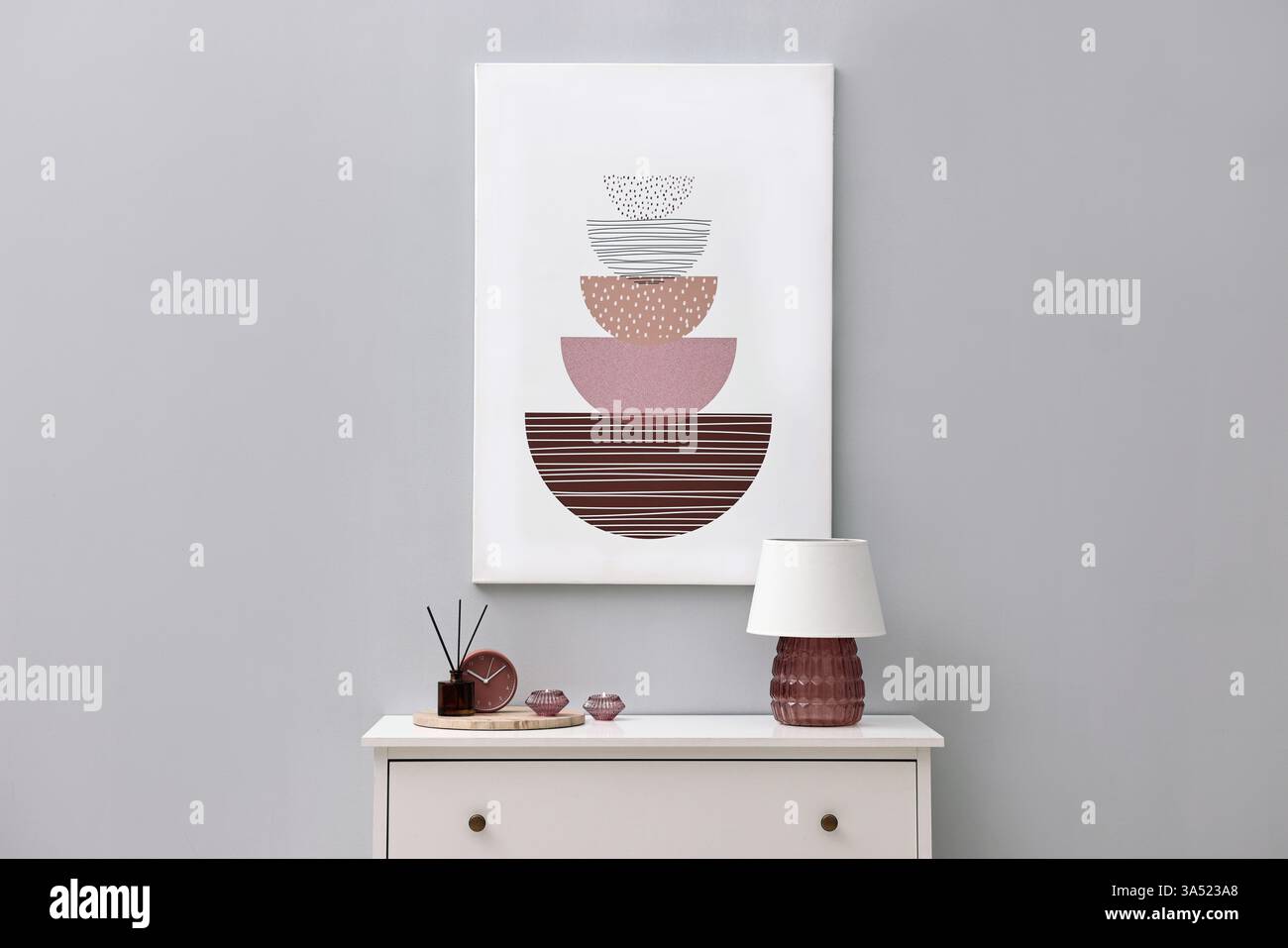 Console table with lamp, clock reed diffuser and candles near light ...