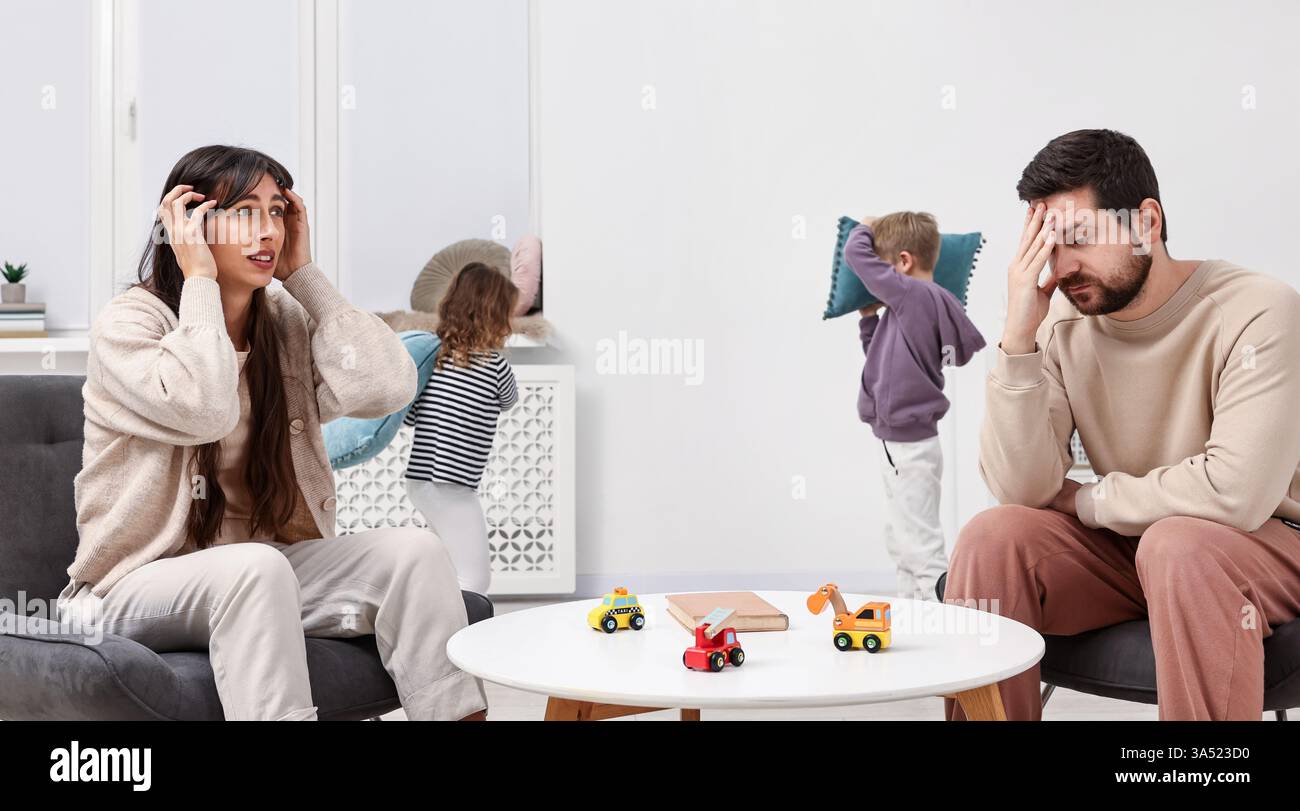Overwhelmed parents and their naughty children at home Stock Photo - Alamy