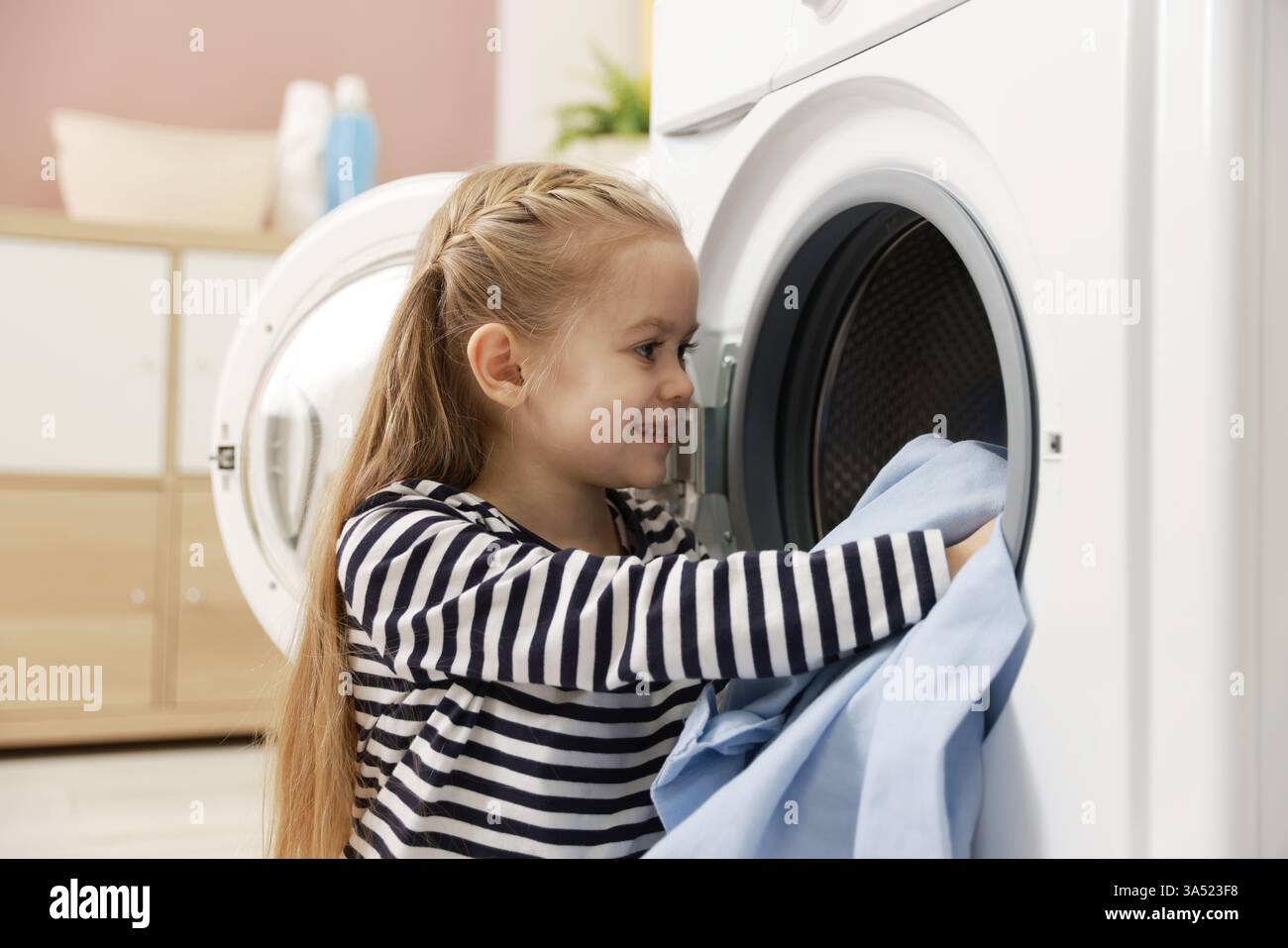 Cute little girl doing laundry at home Stock Photo - Alamy